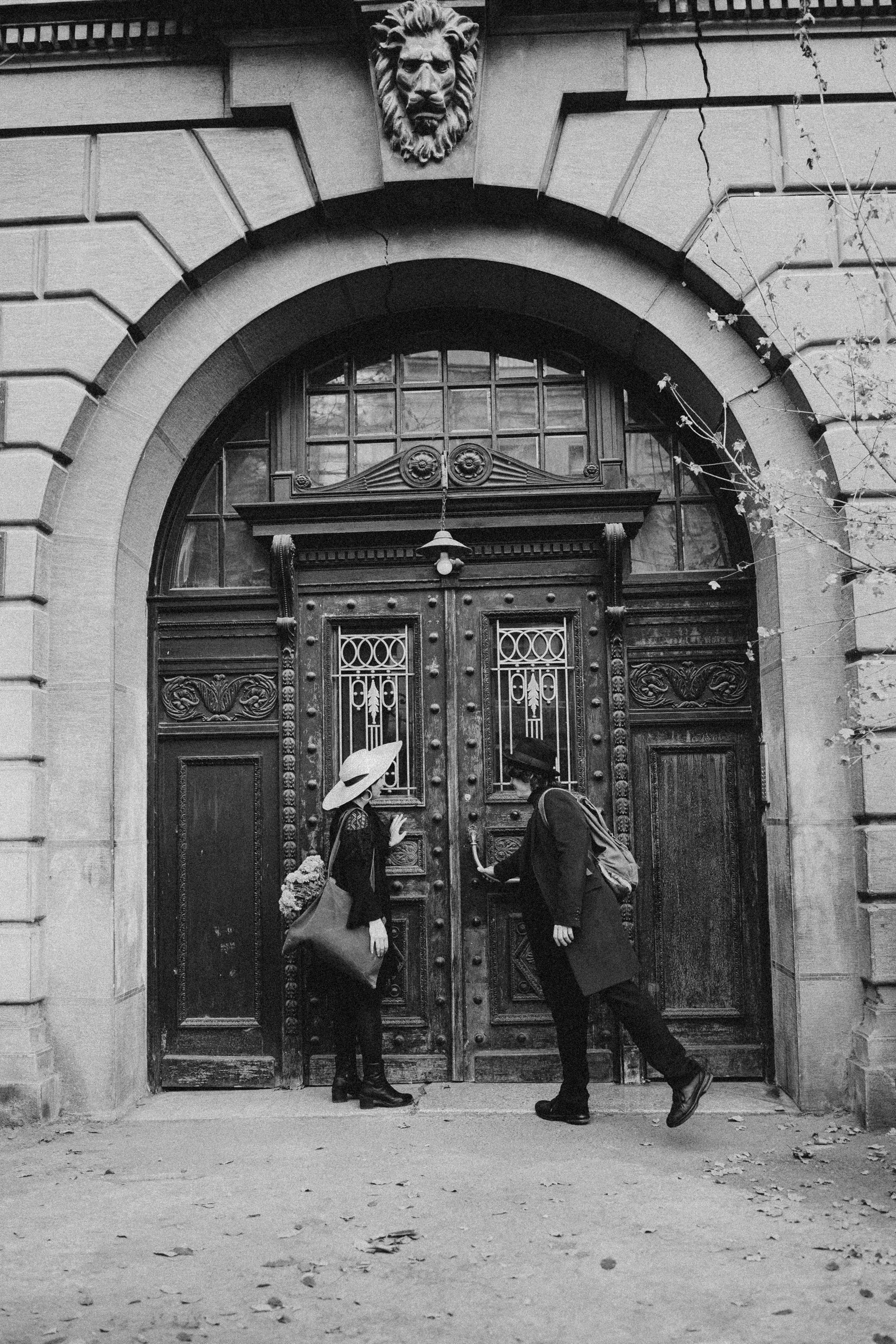 Woman in Hat and Man Trying to Open Wooden Doors · Free Stock Photo