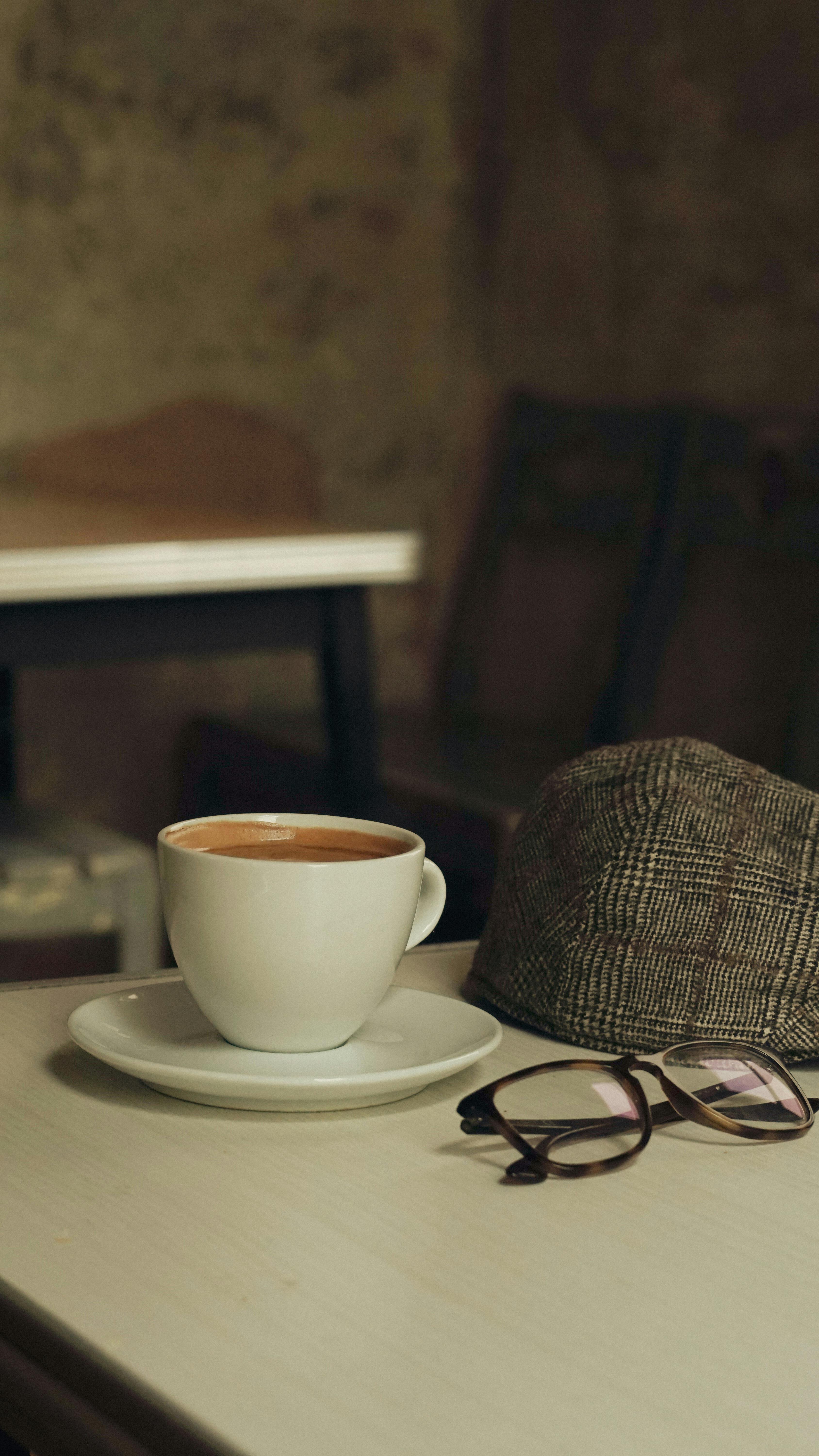 A cup of coffee and a hat on a table · Free Stock Photo