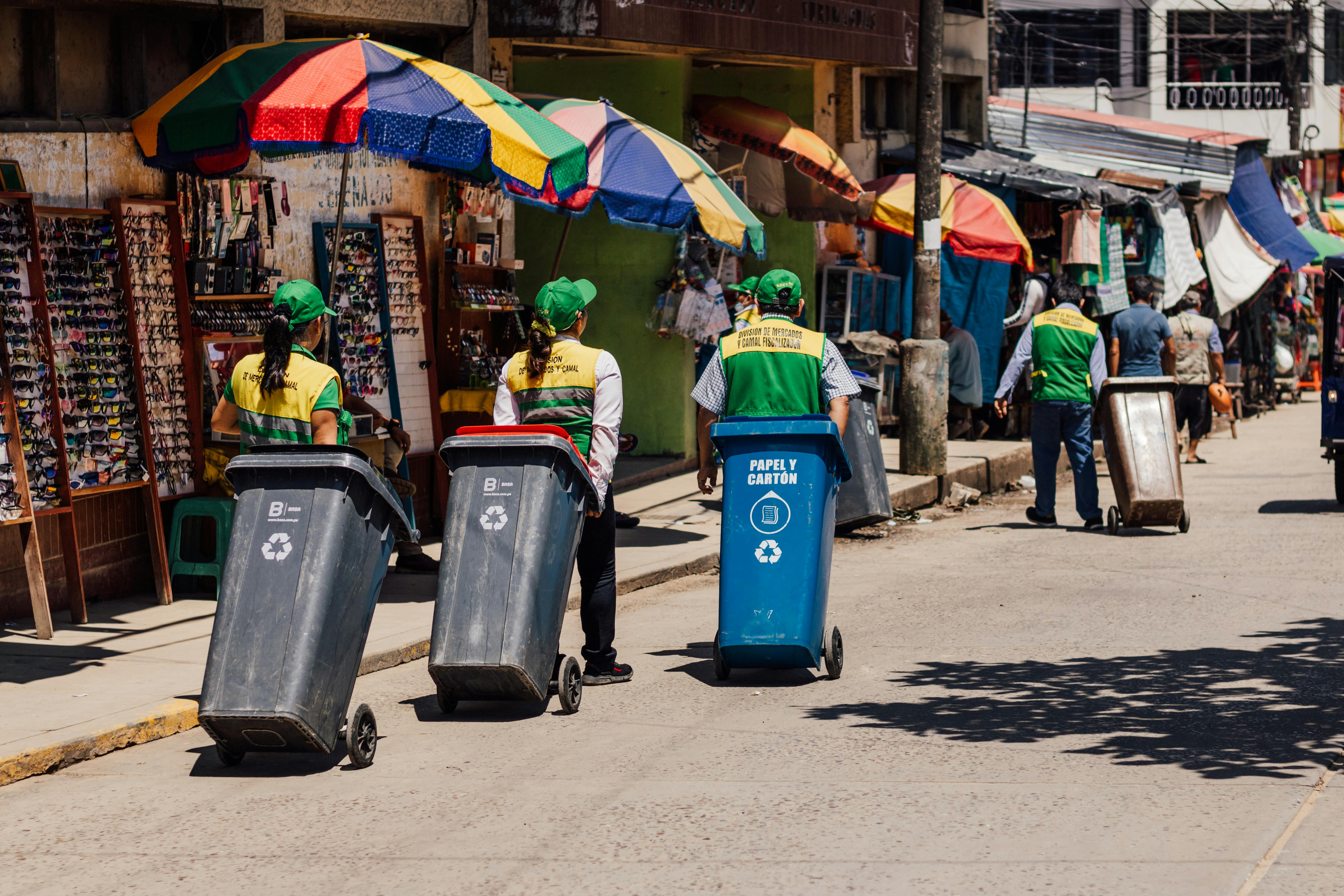Backview of a Street Sweeper holding a Broom and pulling a Trash Bin ...
