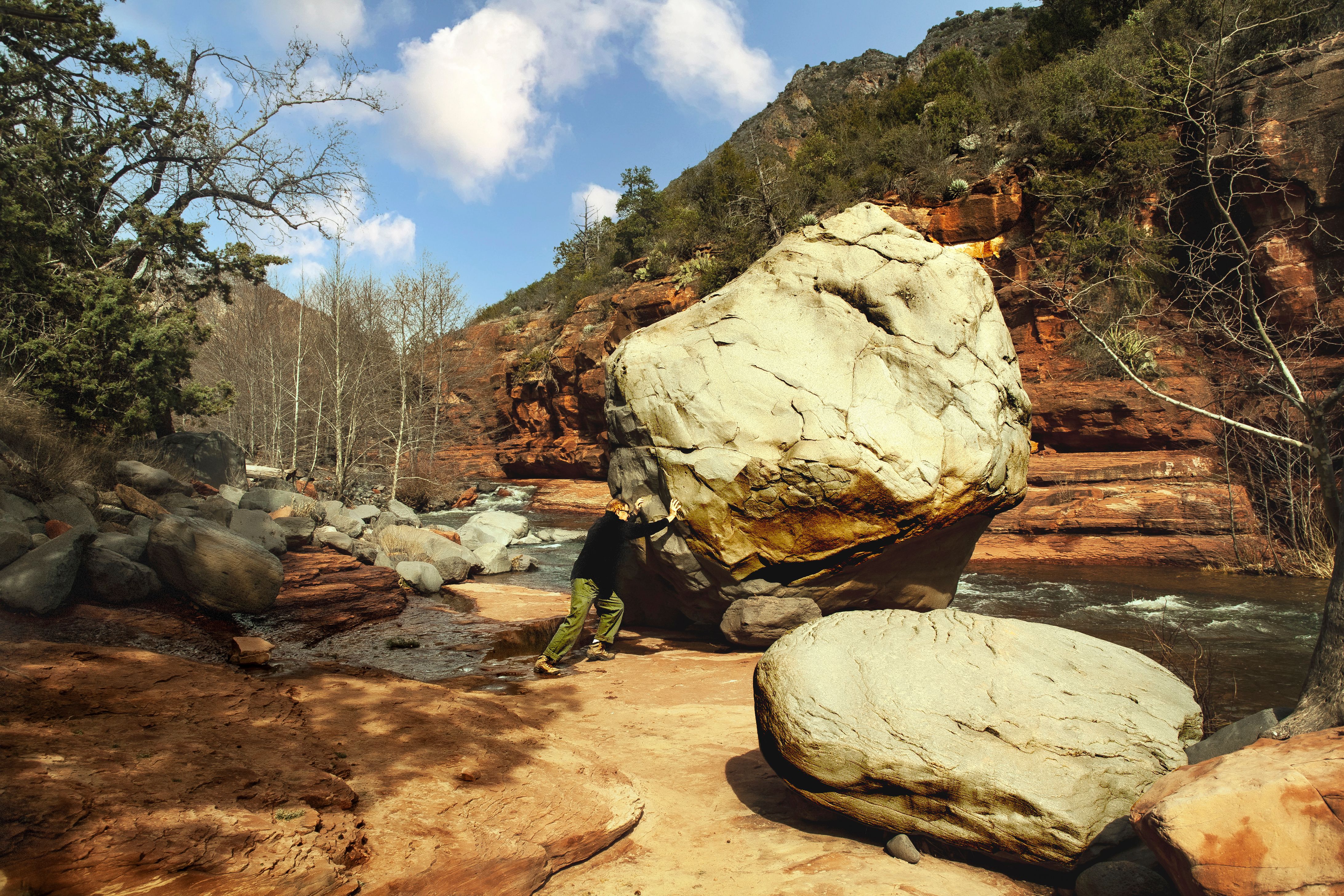 Woman Pushing Large Boulder by Stream in Mountain Valley · Free Stock Photo