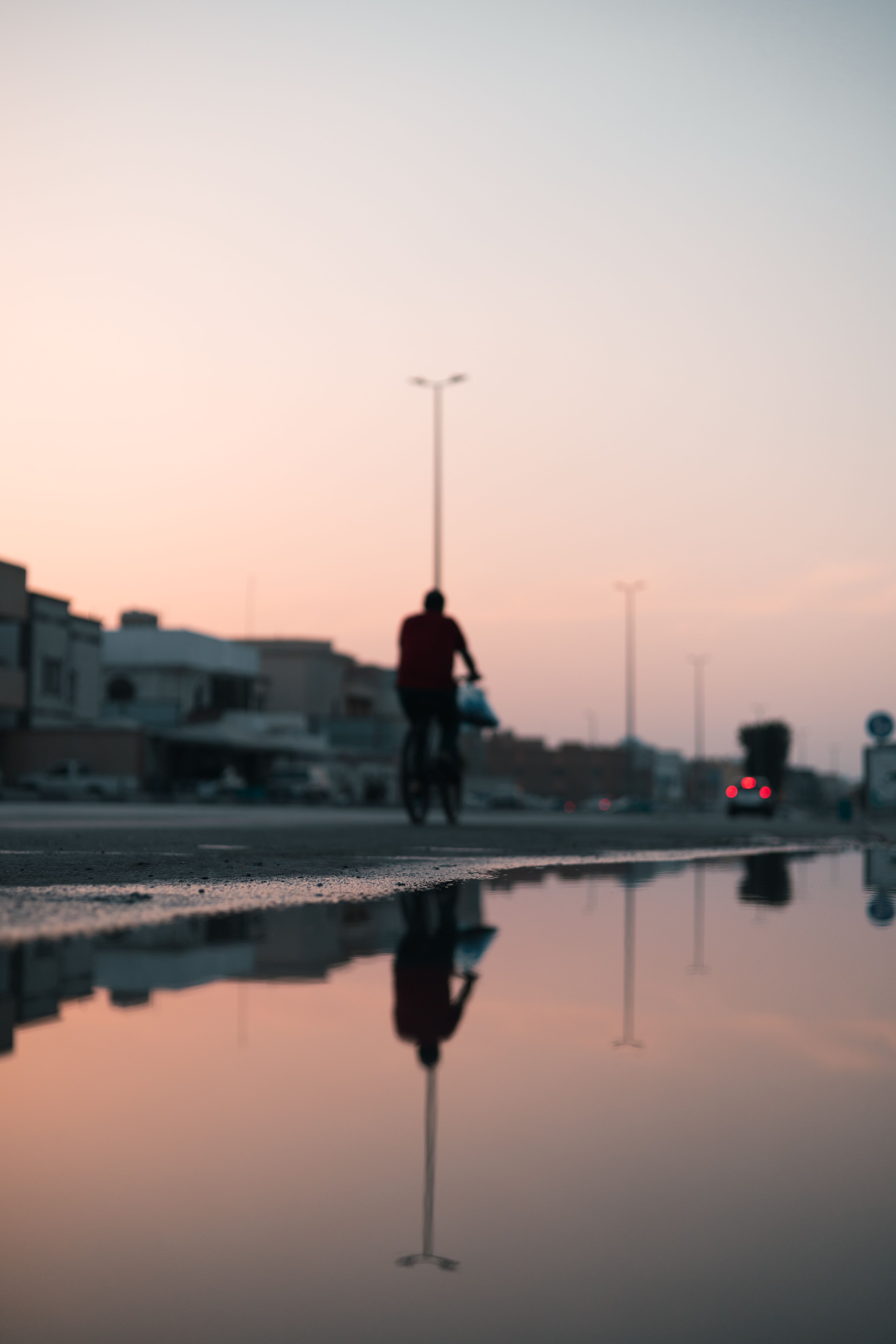 Reflection of Man Riding Bike in Puddle at Dusk · Free Stock Photo