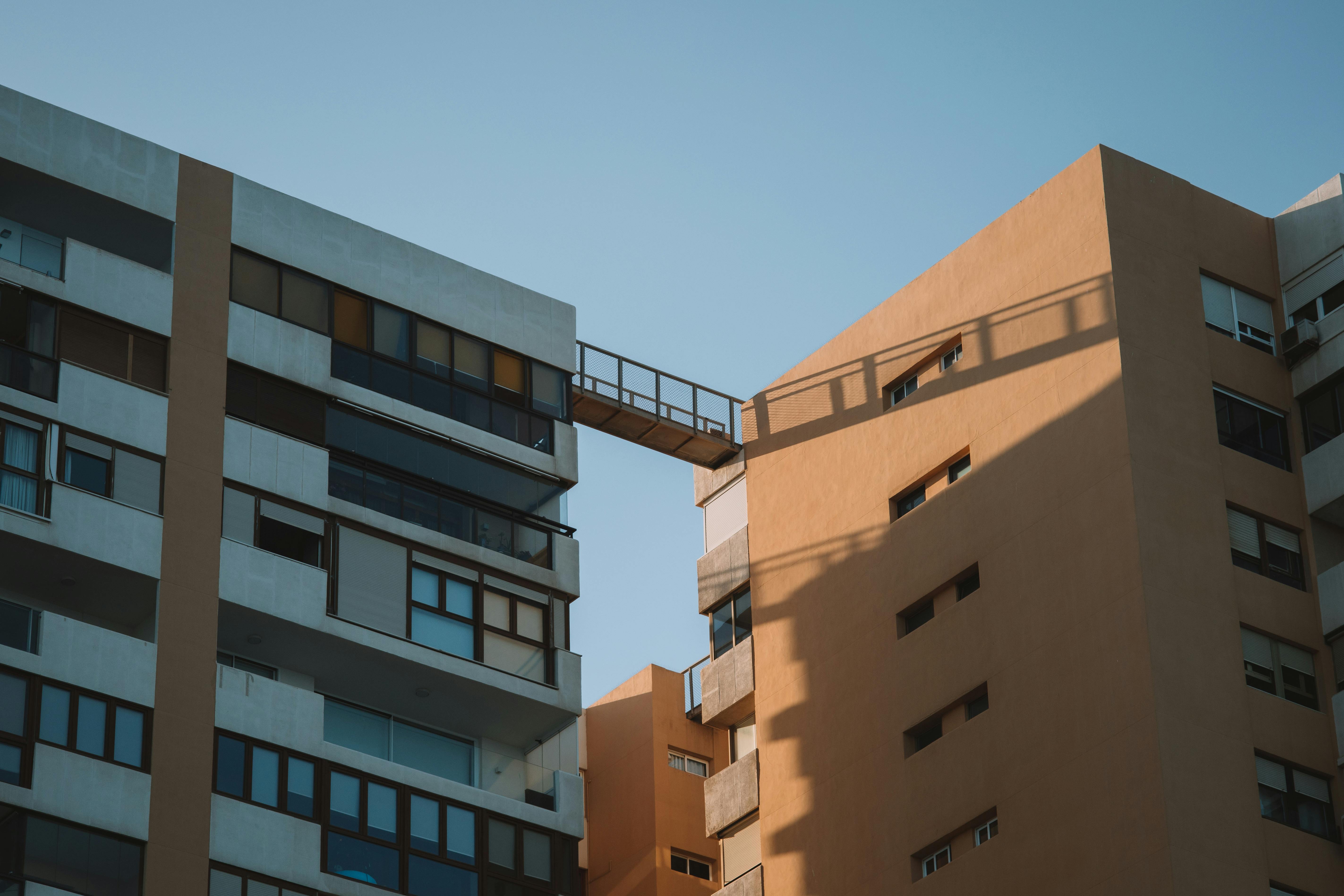 Bridge between Buildings against Blue Sky · Free Stock Photo