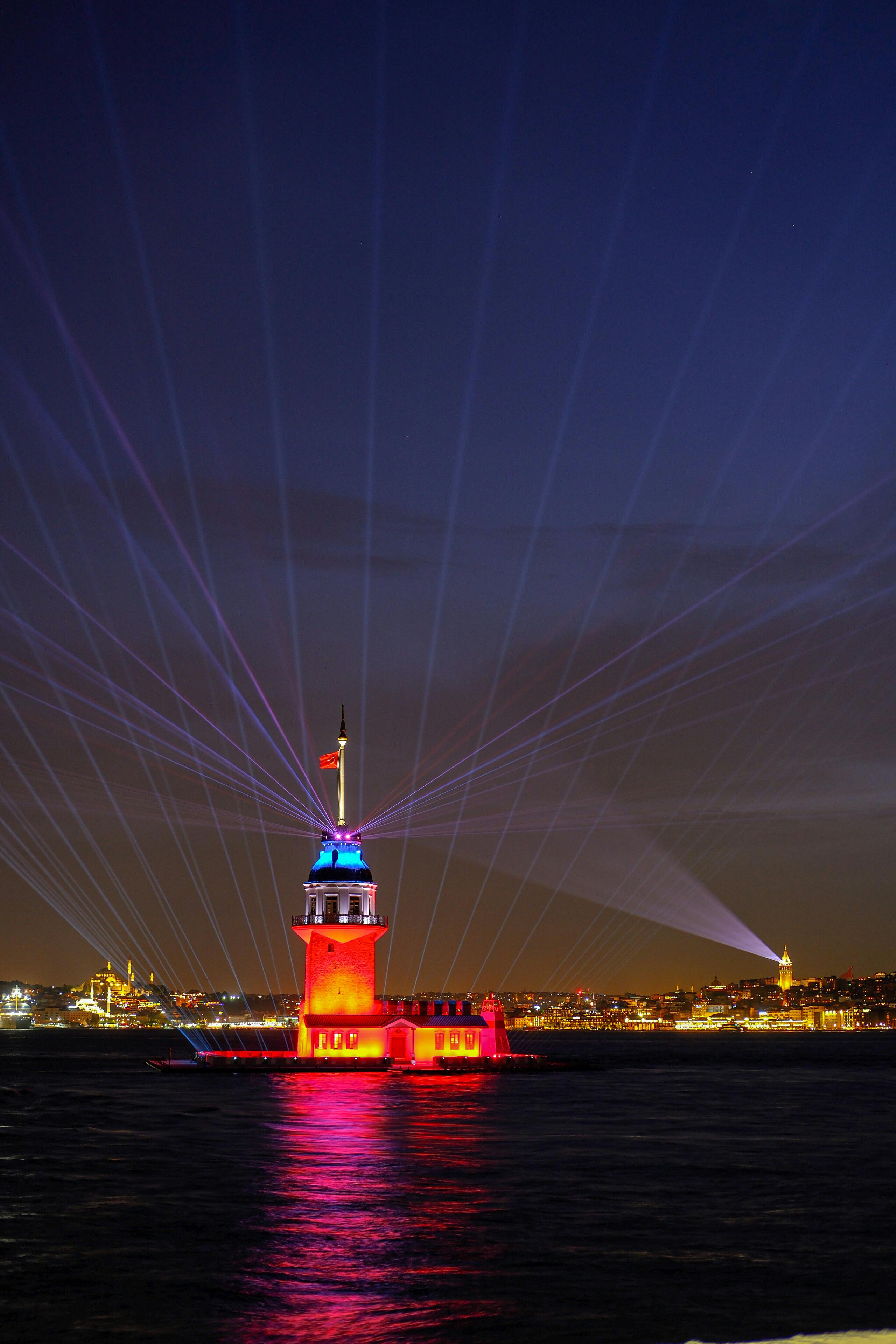 A lighted lighthouse on a body of water · Free Stock Photo