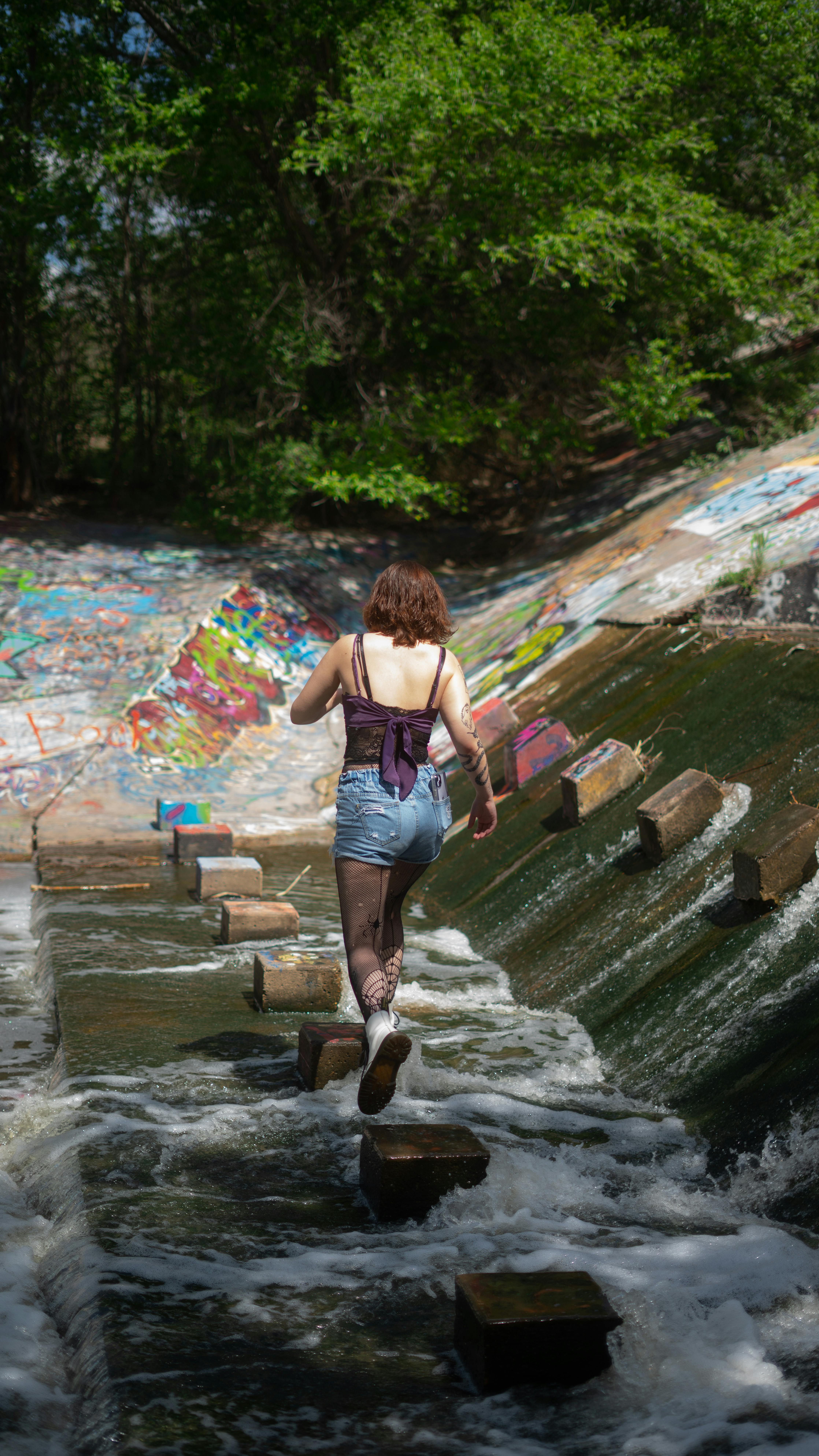 Woman Running over Stone Blocks over Flowing Water on Dam · Free Stock ...