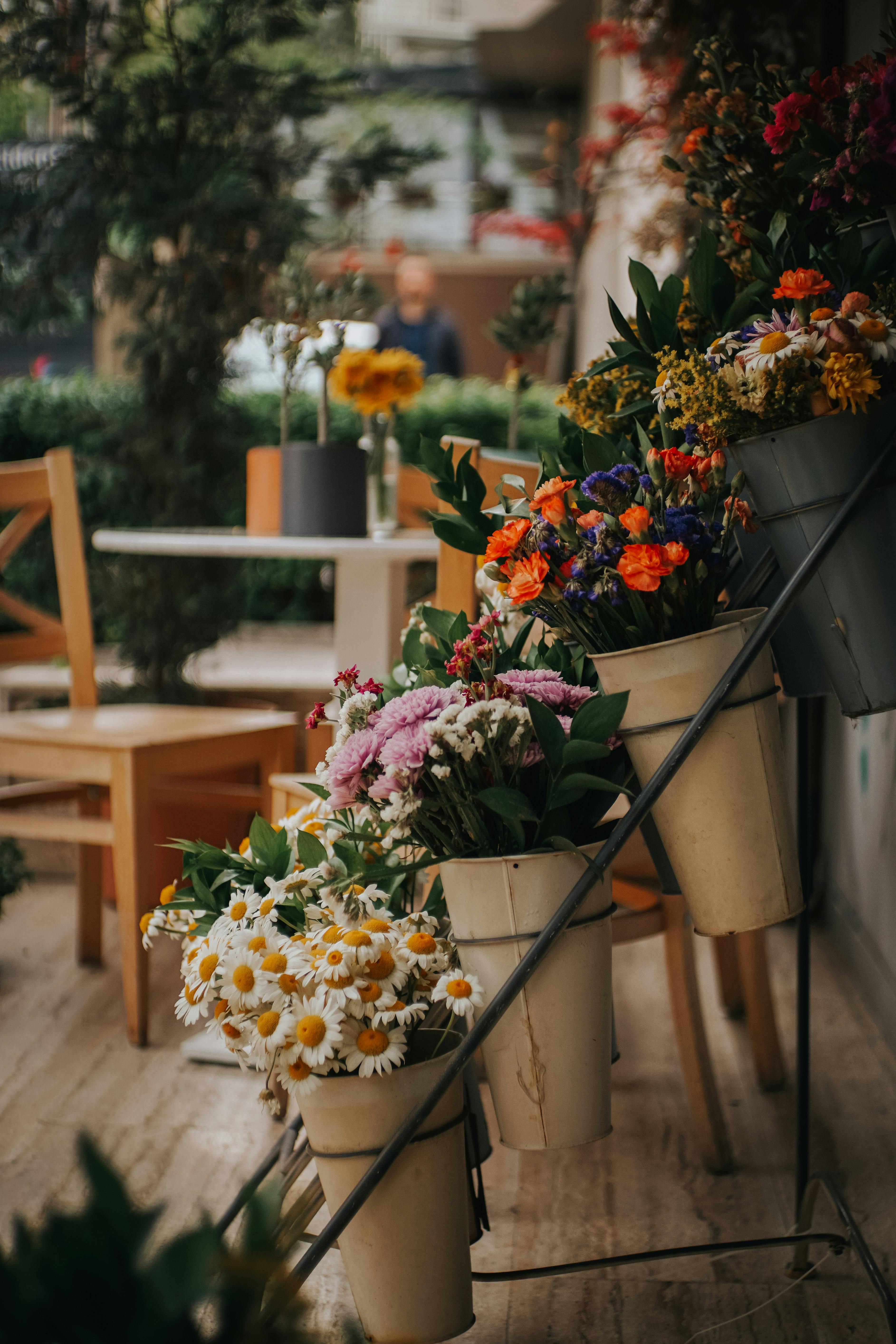 Beautiful Flower Bouquets in Buckets at an Outdoor Cafe · Free Stock Photo