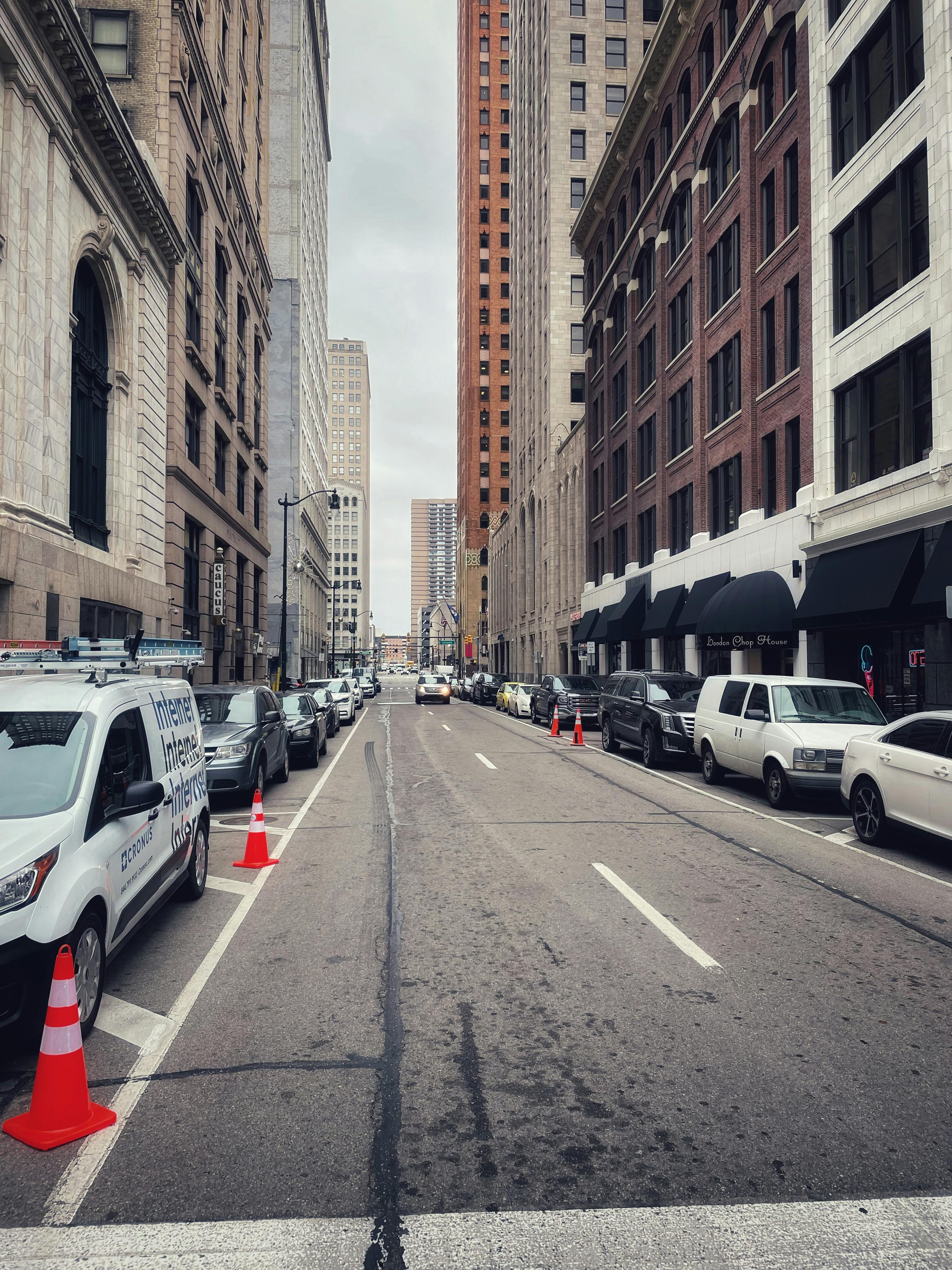 View of a Street between Tall Buildings with Cars Parked on Both Sides ...