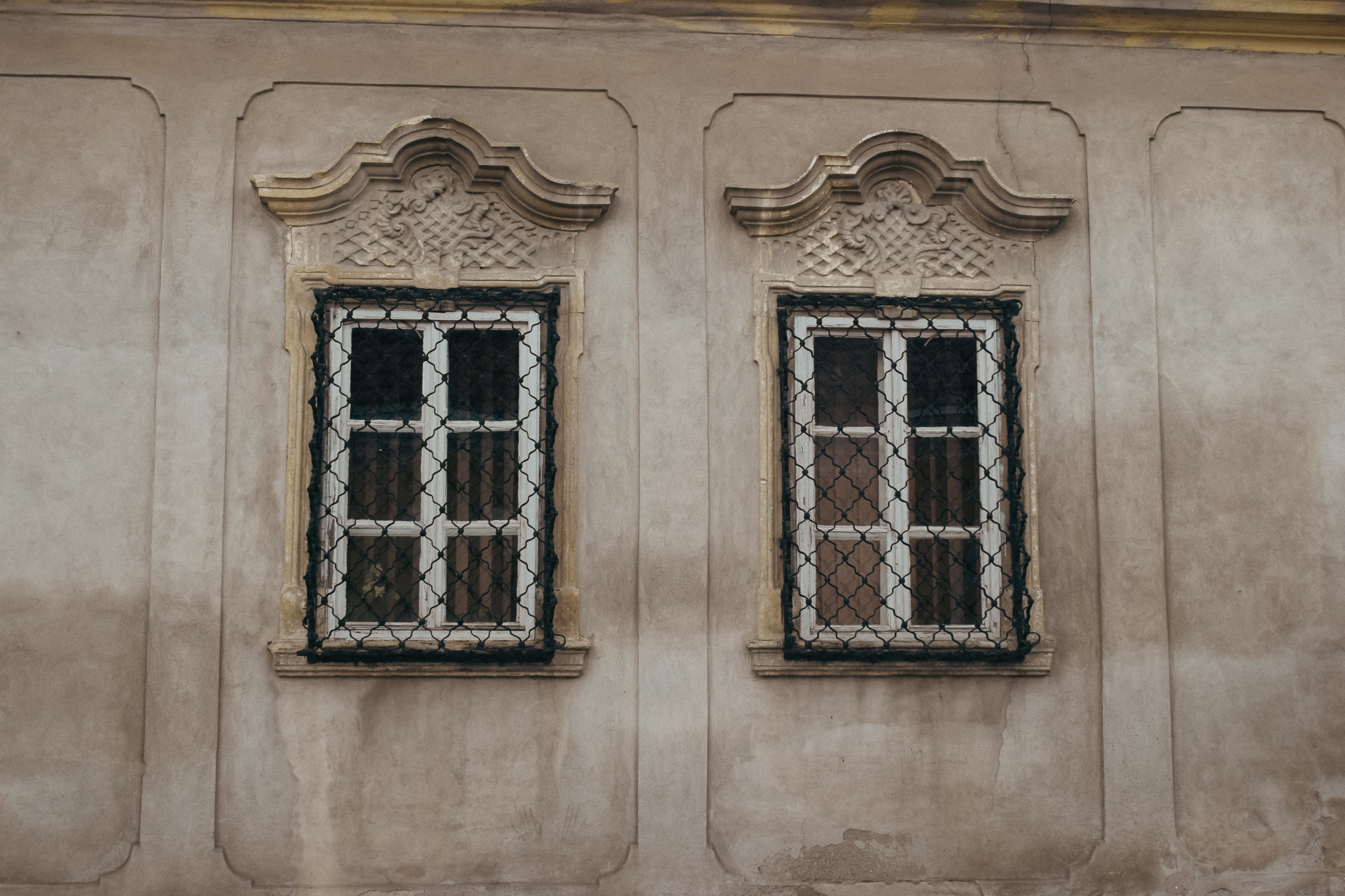 Two windows on a building with ornate designs · Free Stock Photo