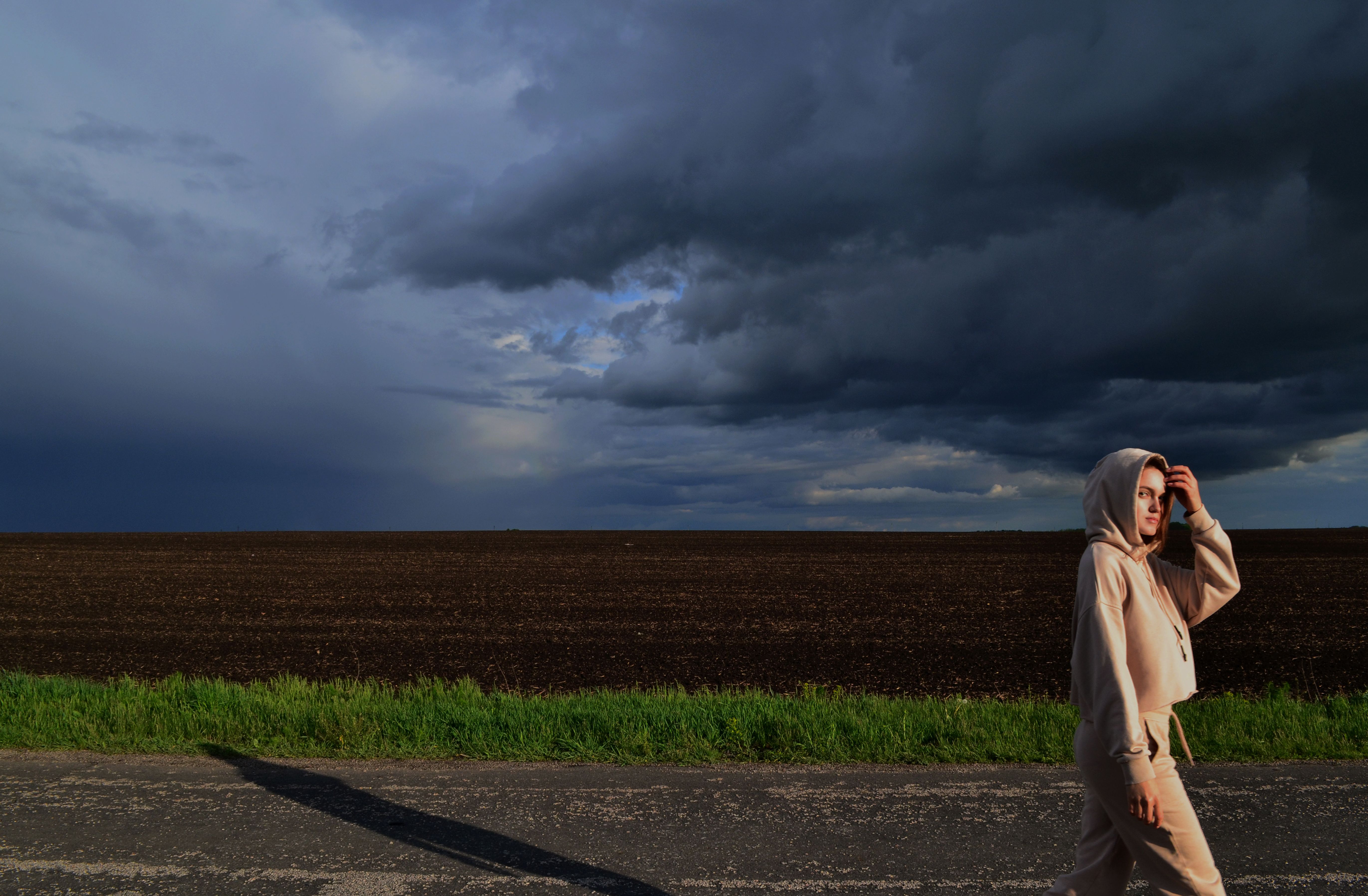 Woman Walking on a Field Under Dramatic Stormy Sky · Free Stock Photo