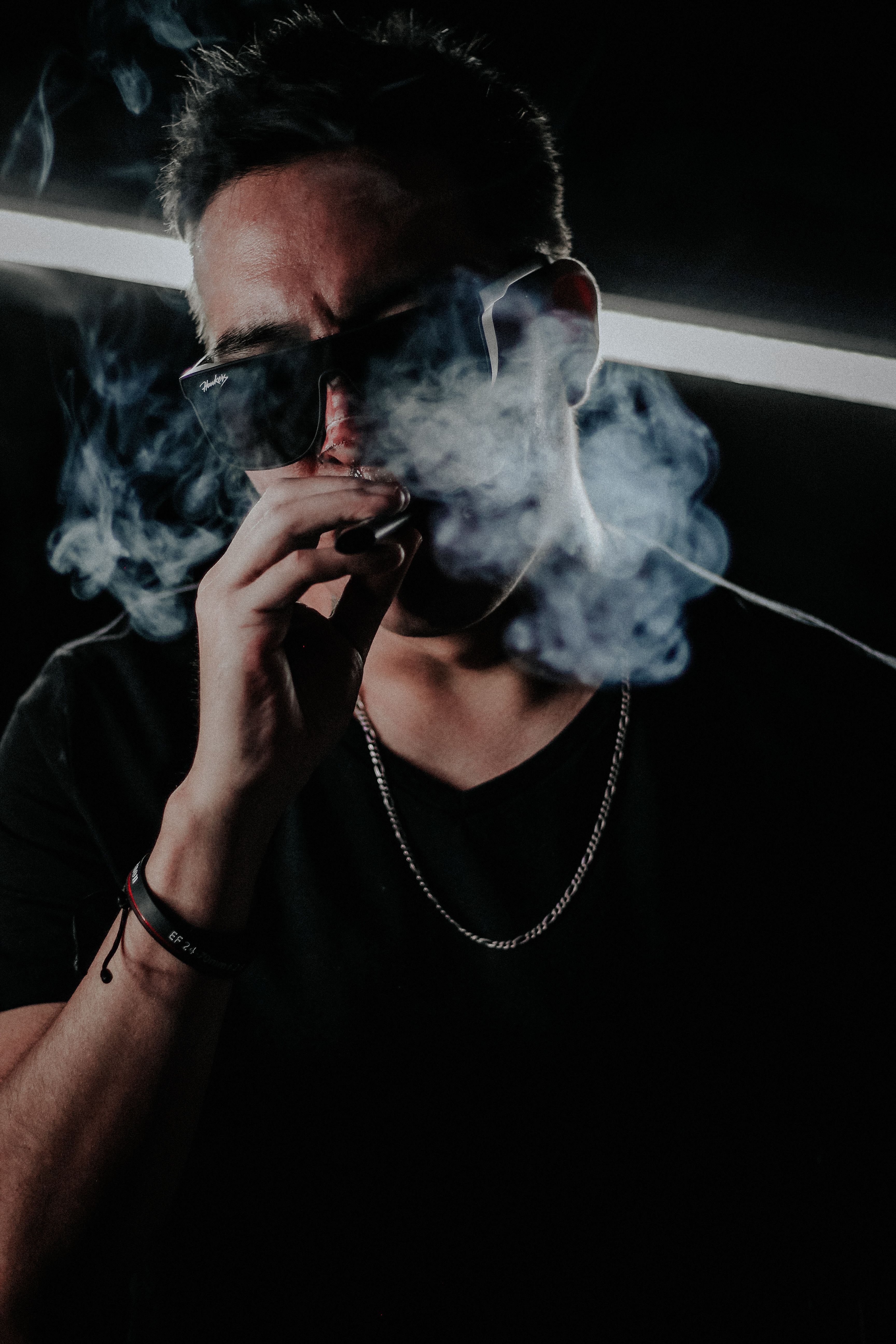 A man smoking a cigarette in a dark room · Free Stock Photo