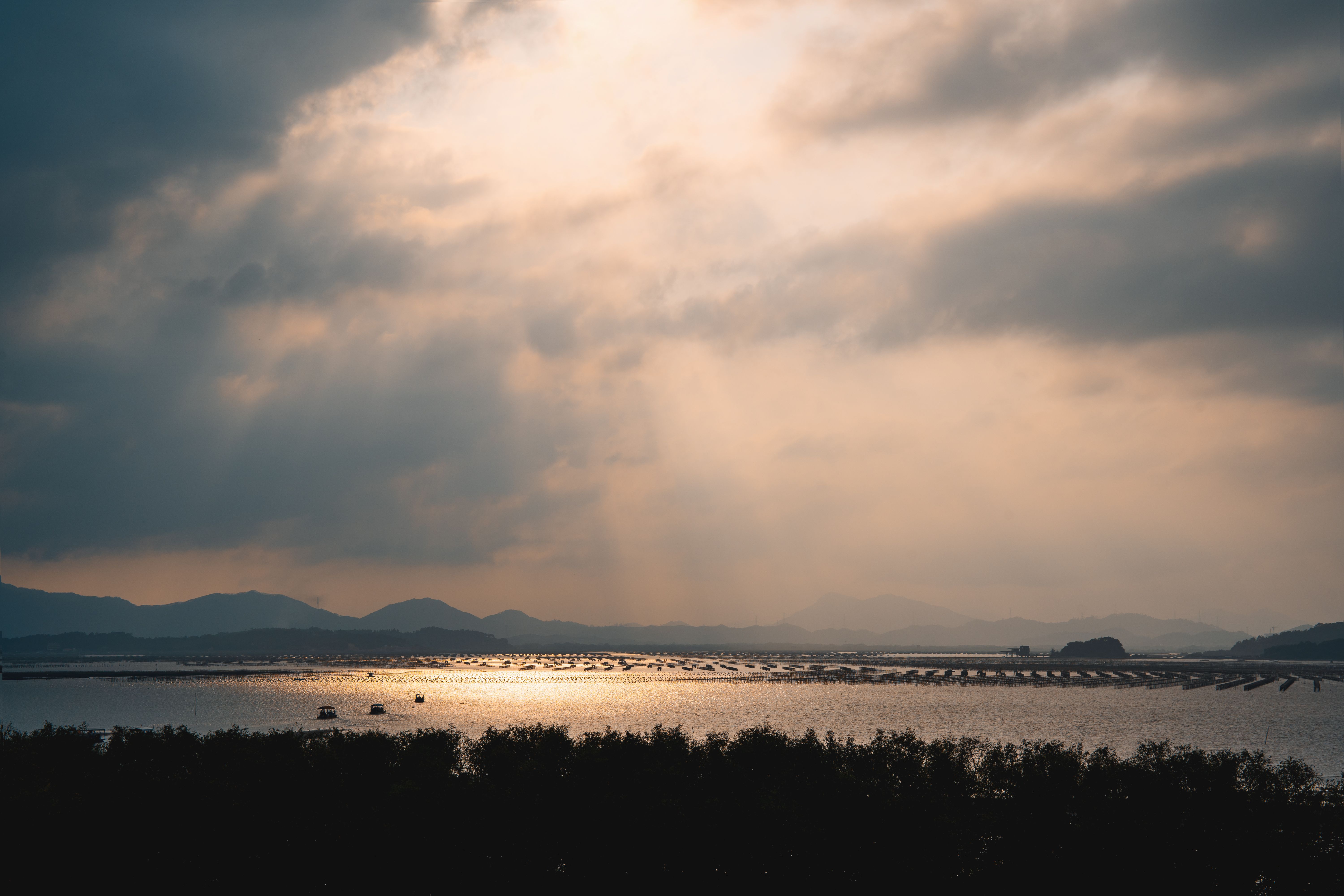 Sunlight from behind Clouds over Lake at Sunset · Free Stock Photo