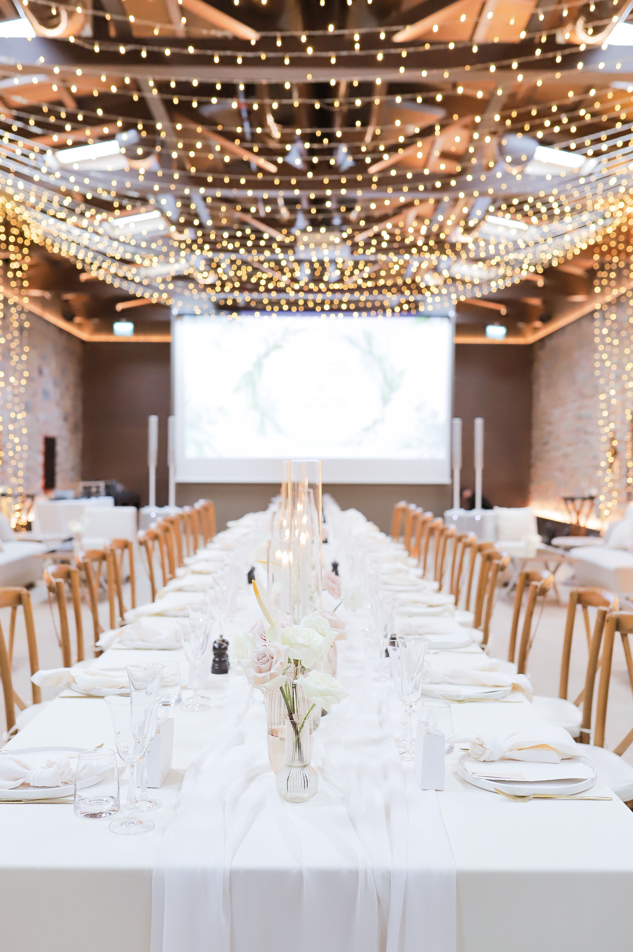 A long table with white linens and white lights · Free Stock Photo