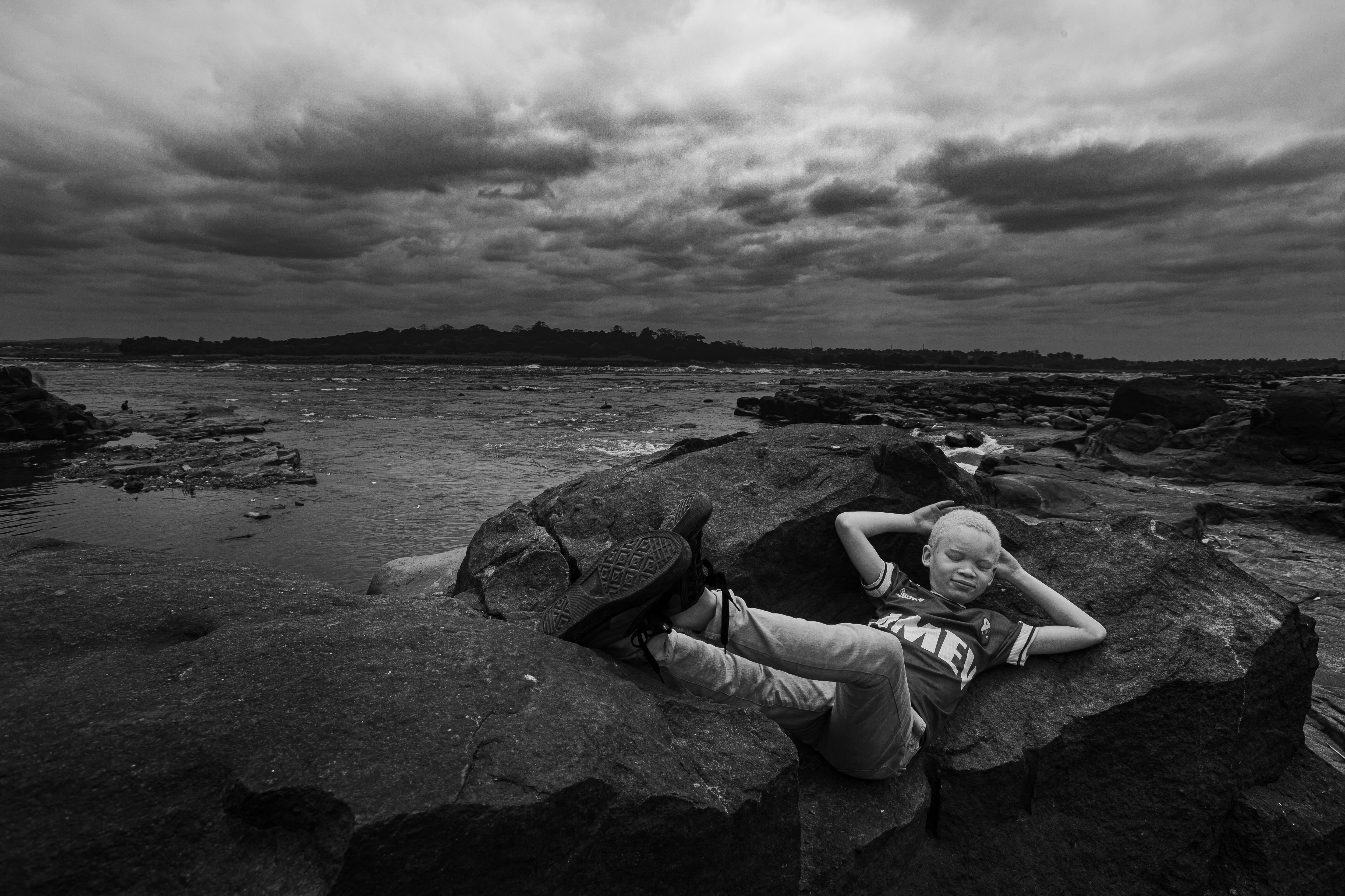 A Boy Lying on the Rocks on a Shore · Free Stock Photo