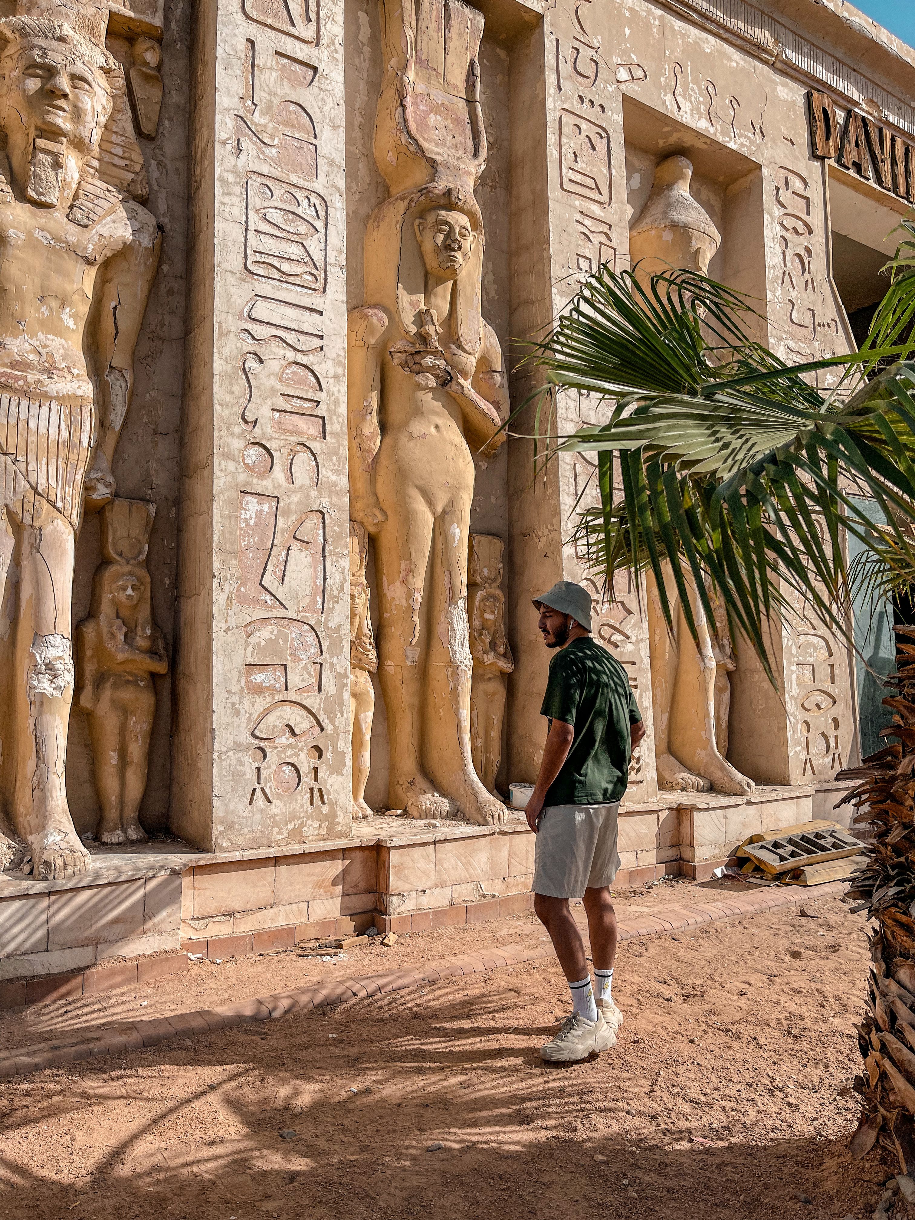 Man Standing by Ancient Sculptures on Wall in Egypt · Free Stock Photo