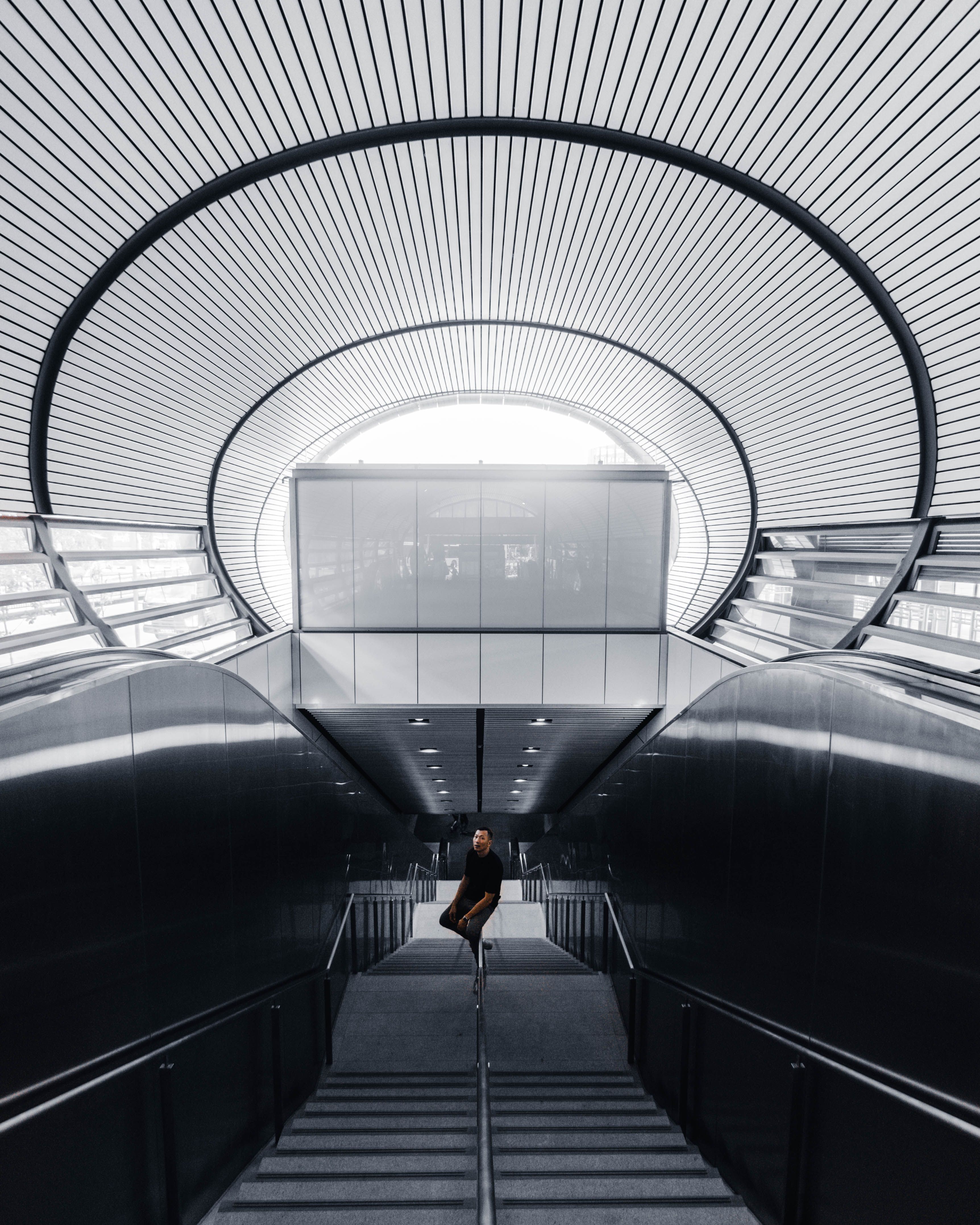 Man Sitting on Railing by Stairs in Modern Tunnel · Free Stock Photo