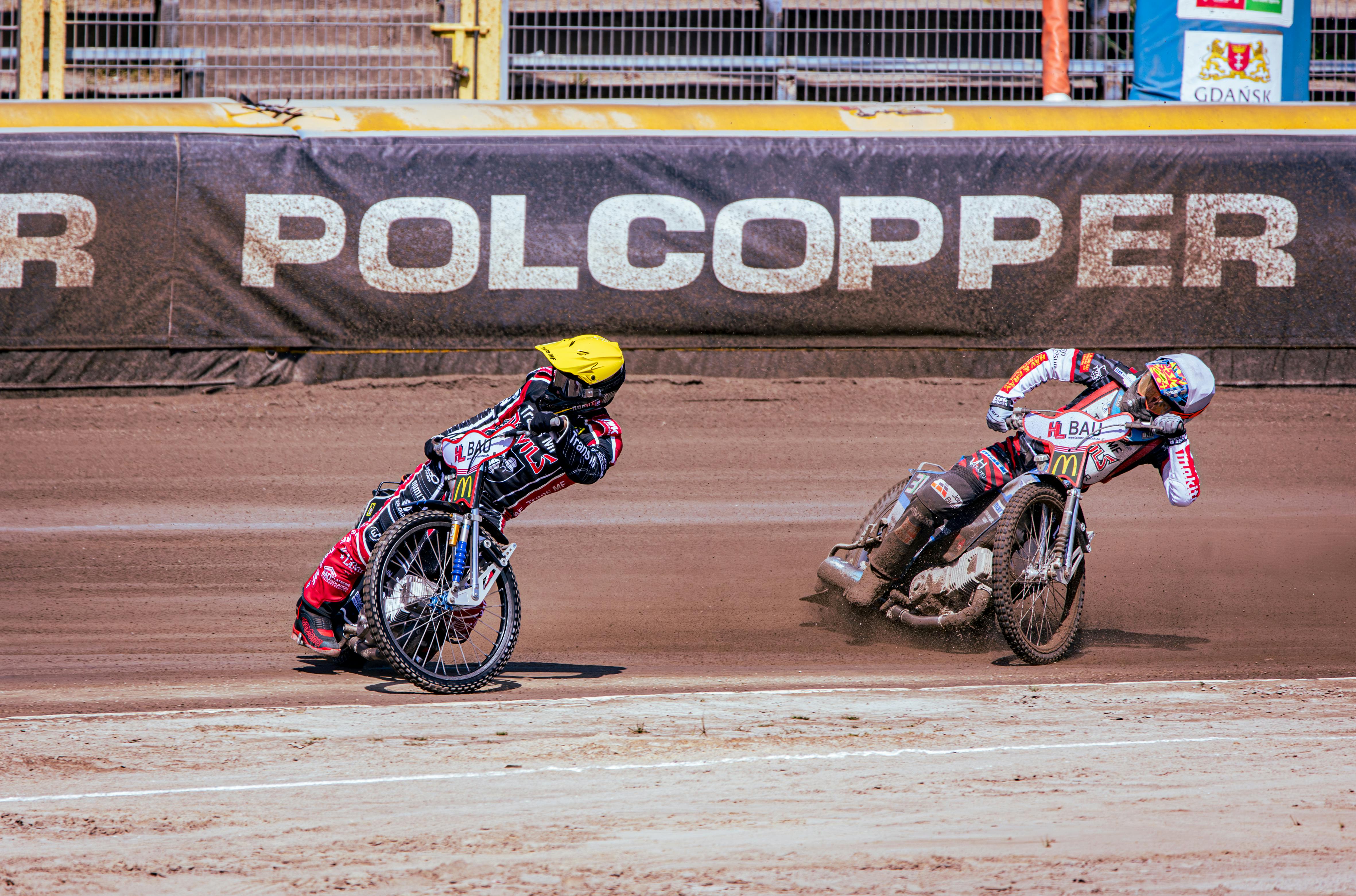 Two dirt bike riders racing on a dirt track · Free Stock Photo
