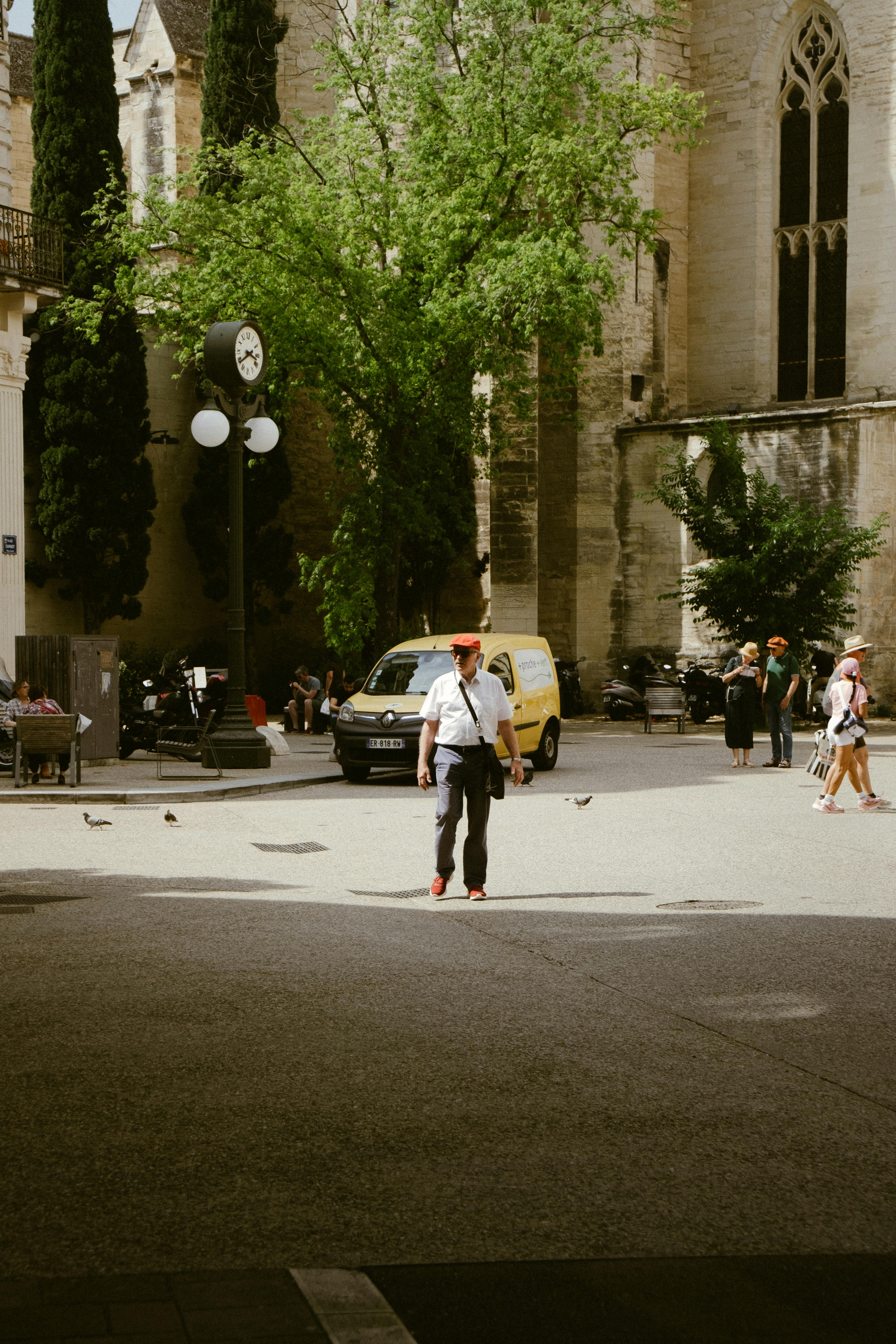 Photo of a Man Walking on a City Square, and a Gothic Church in ...