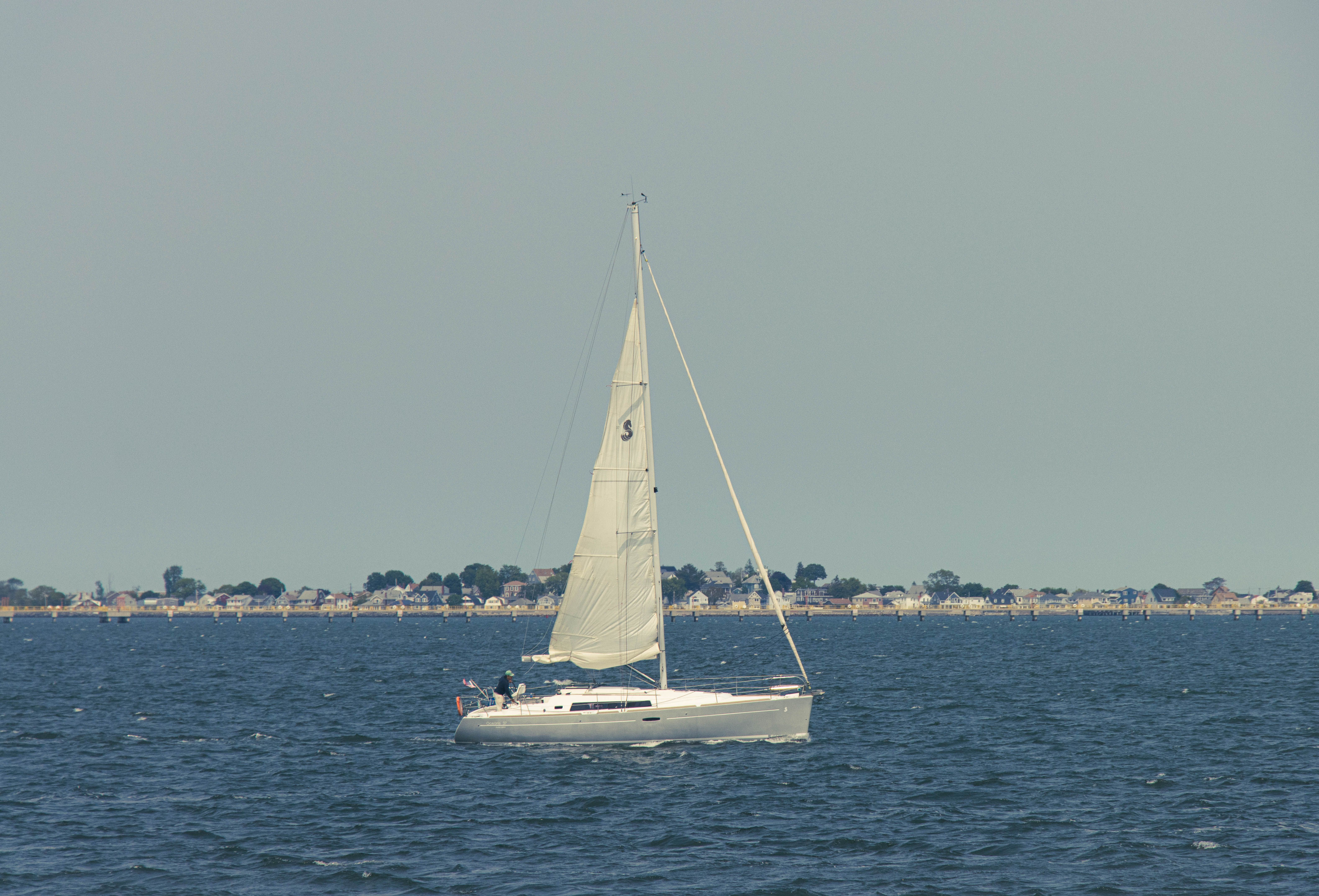 Sailboat Sailing with Sea Coast behind · Free Stock Photo