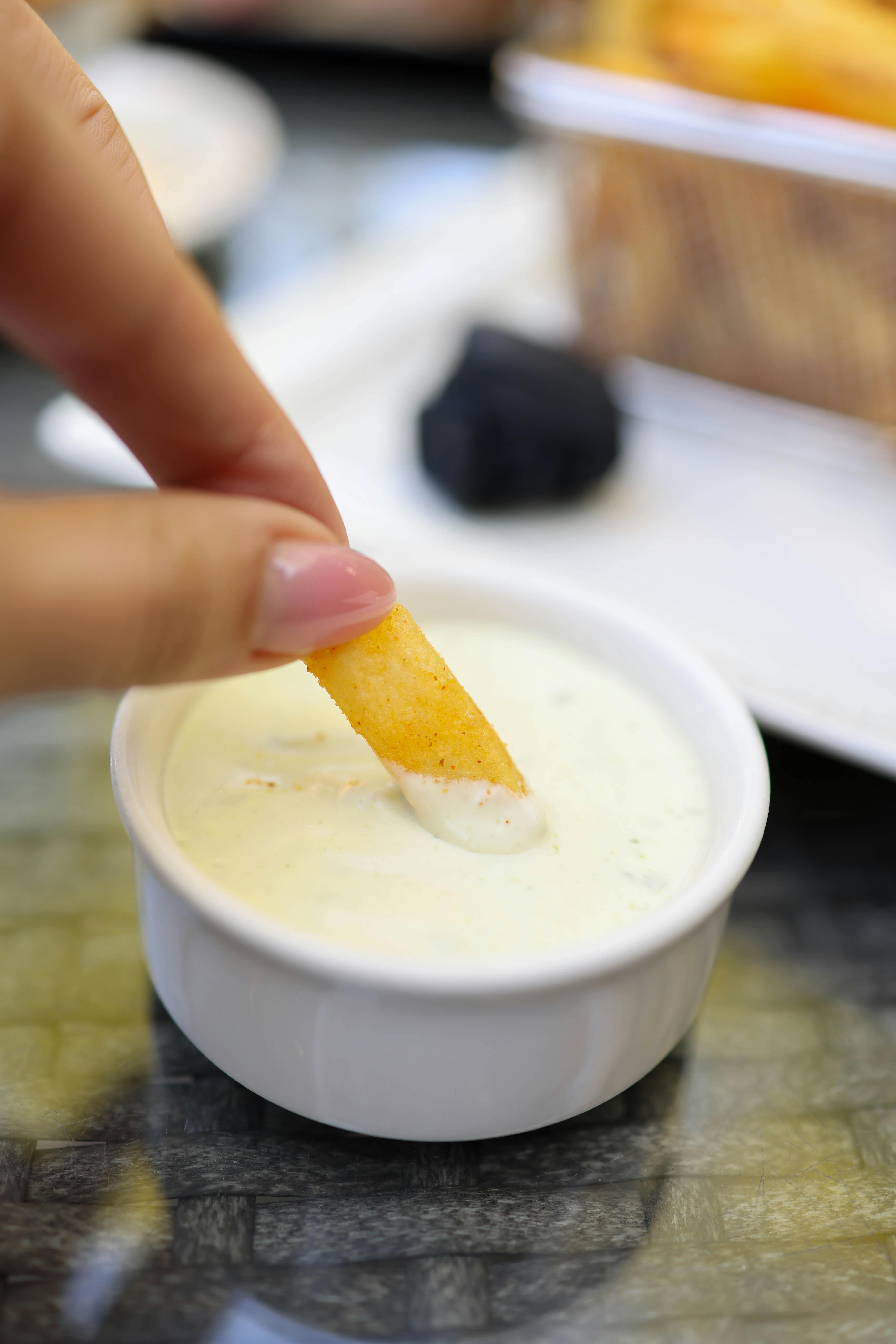 Fingers of a Woman Dipping a Fry in a White Dipping Sauce · Free Stock ...