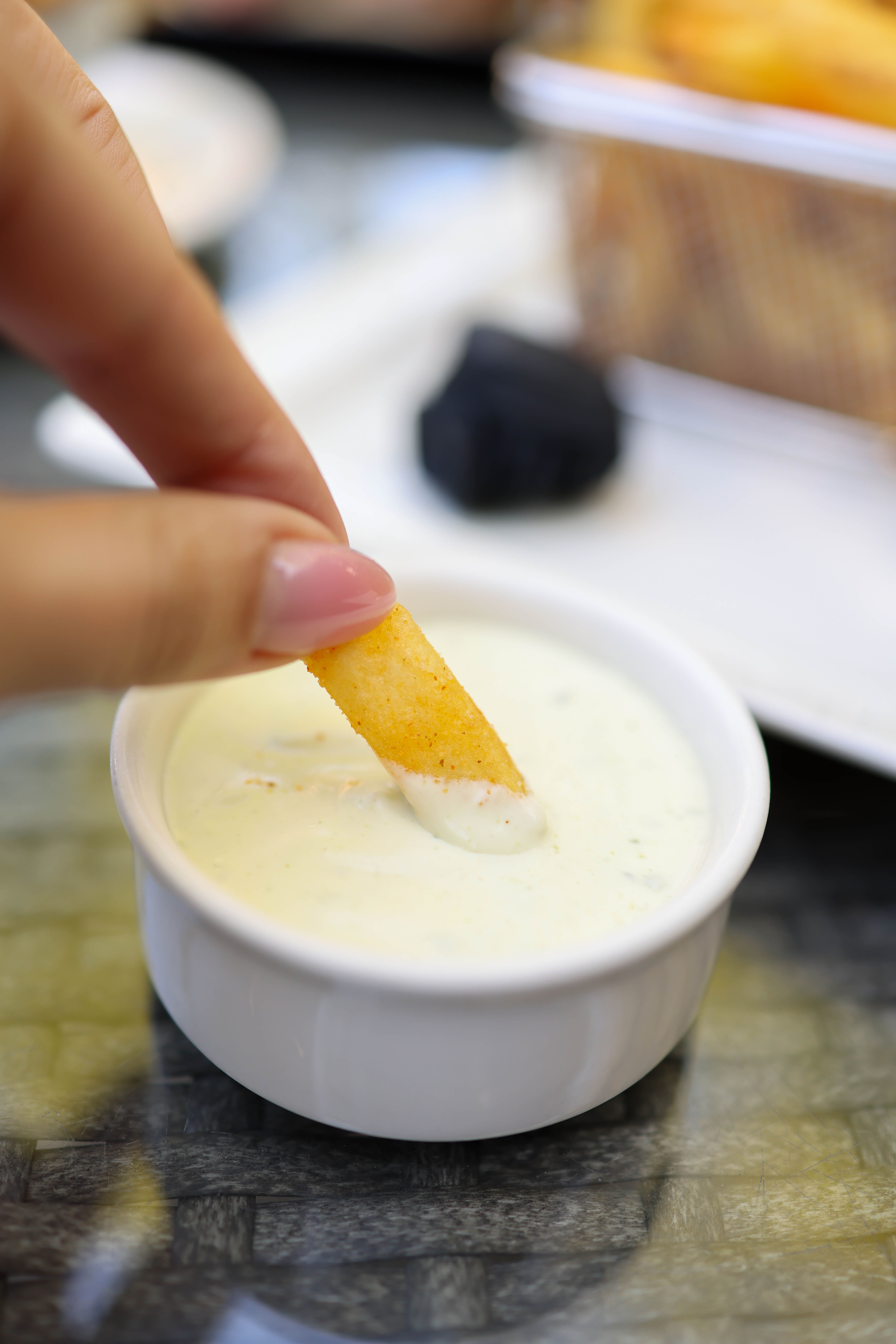 Fingers of a Woman Dipping a Fry in a White Dipping Sauce · Free Stock ...