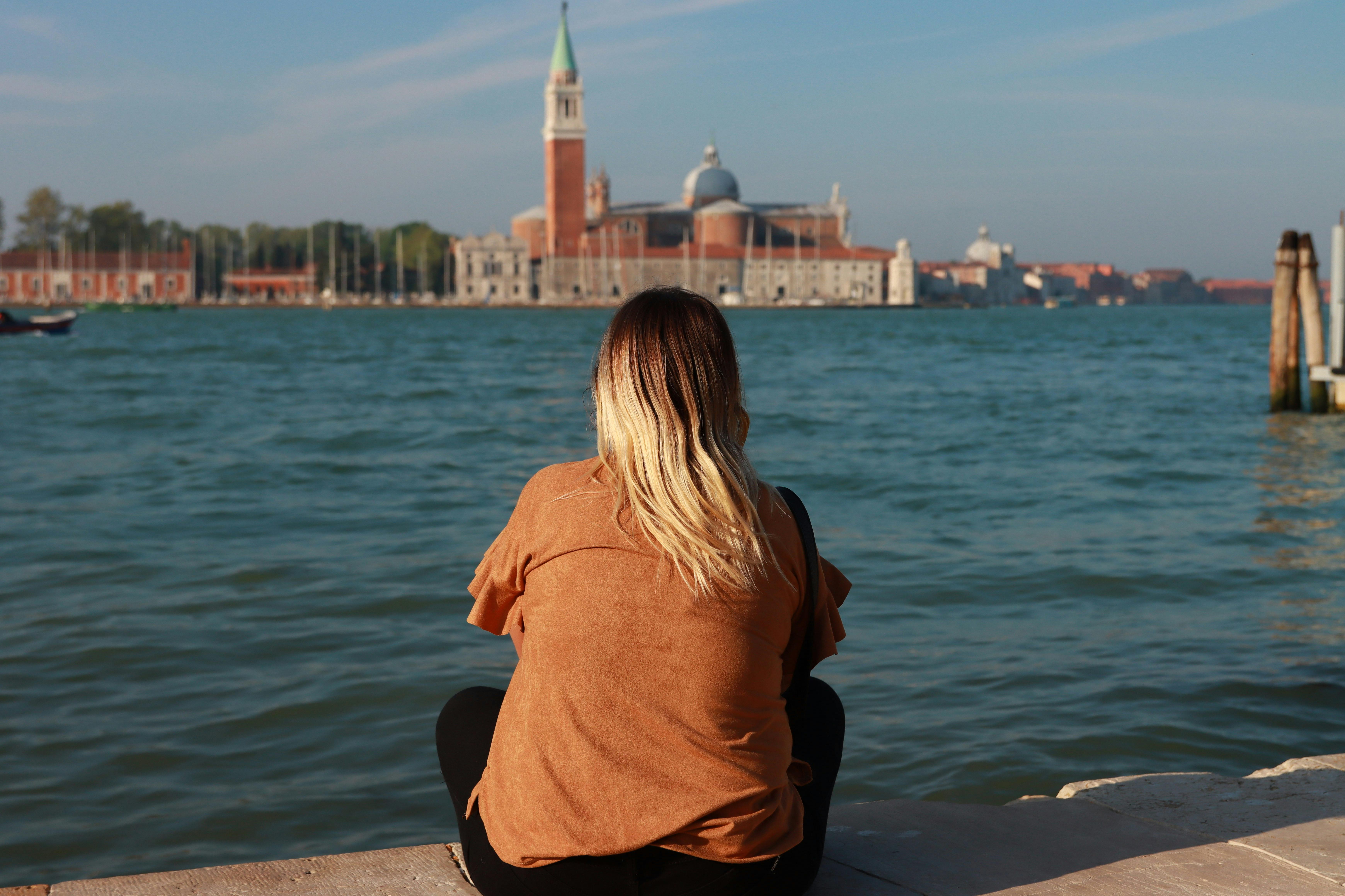 Back View of a Woman Sitting by a Canal and Contemplating Architecture ...
