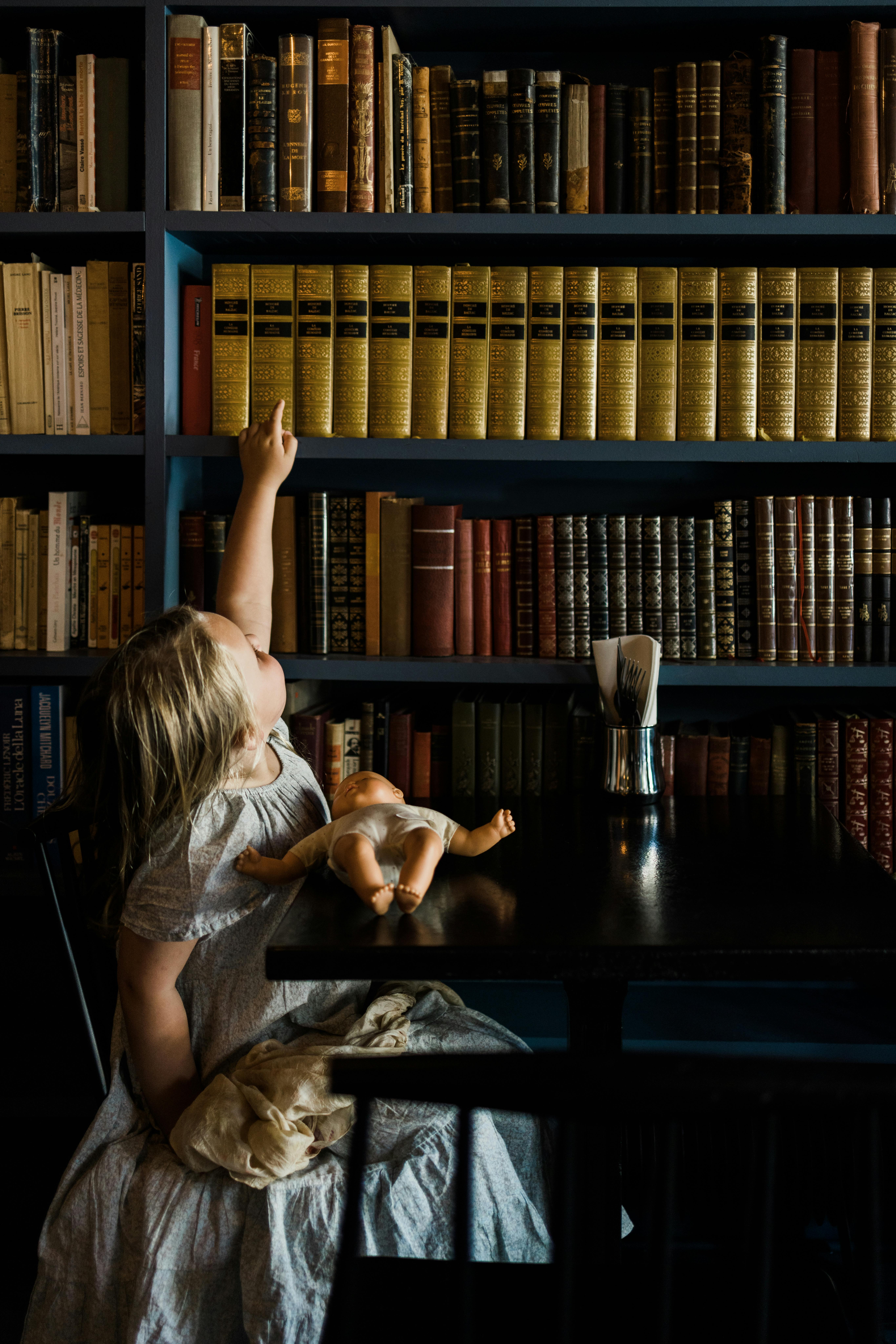 Sitting Girl Pointing on a Book · Free Stock Photo