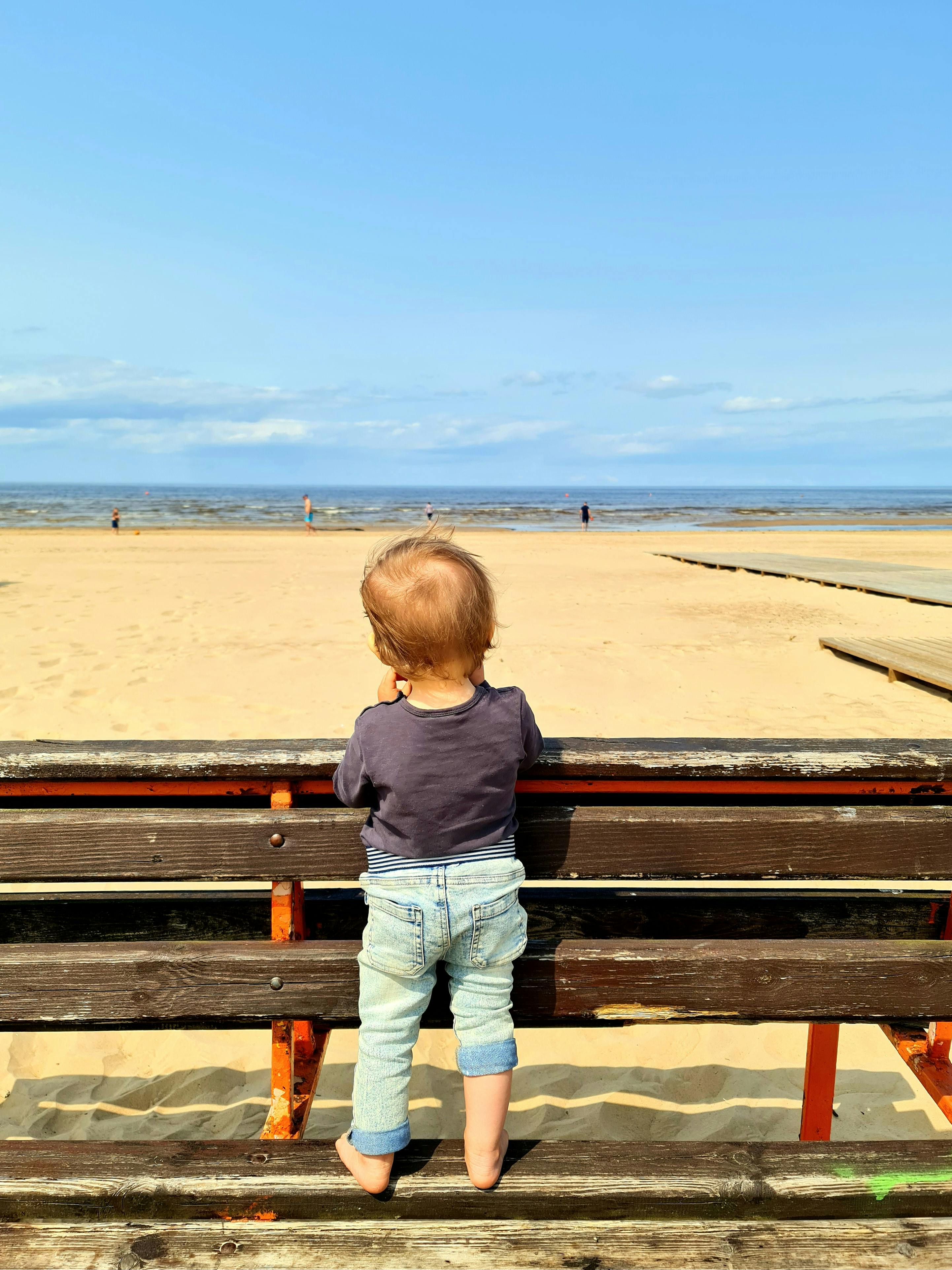 A Little Boy next to a Bench on a Beach · Free Stock Photo