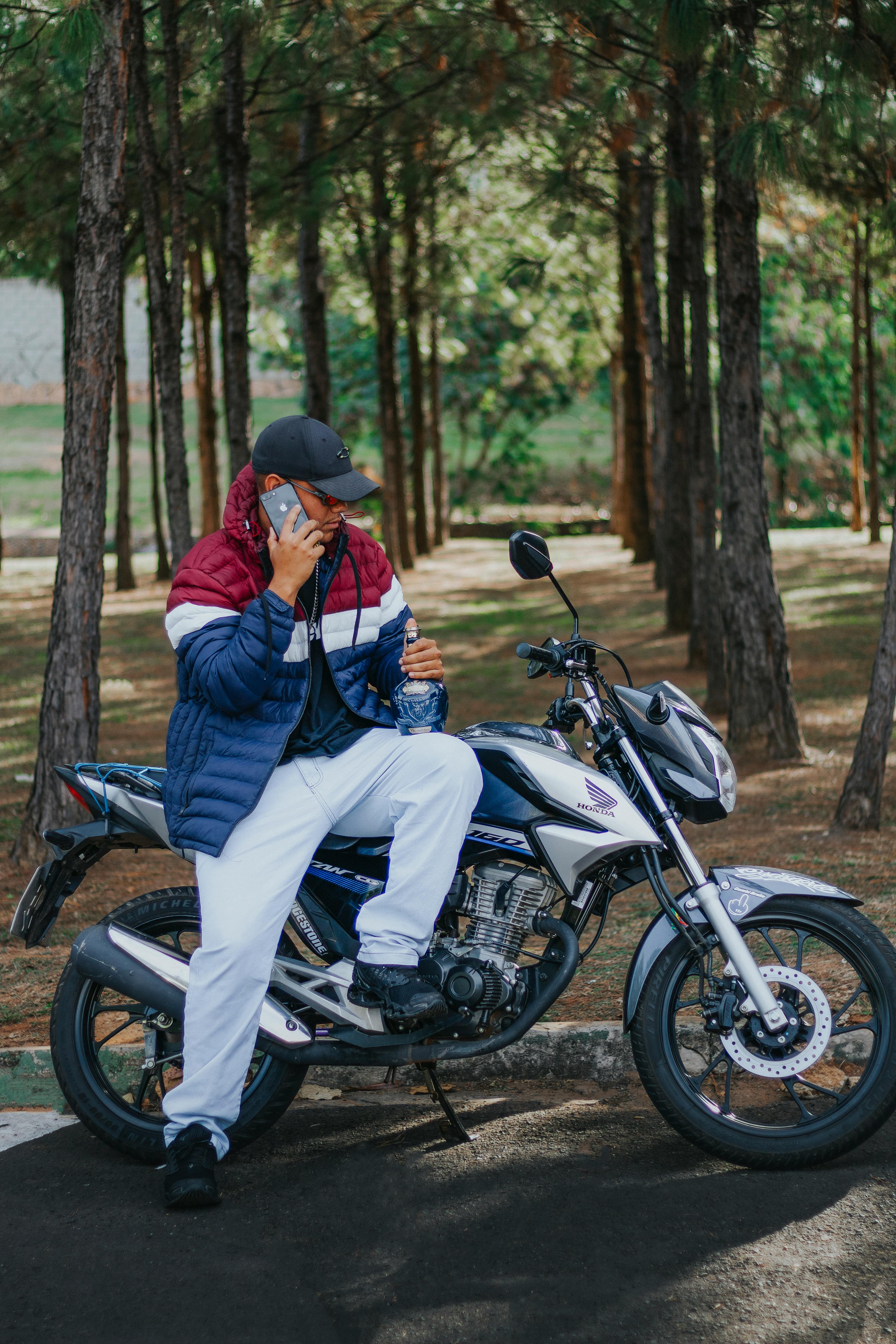 A Man Sitting on a Motorcycle Talking on a Smart Phone · Free Stock Photo