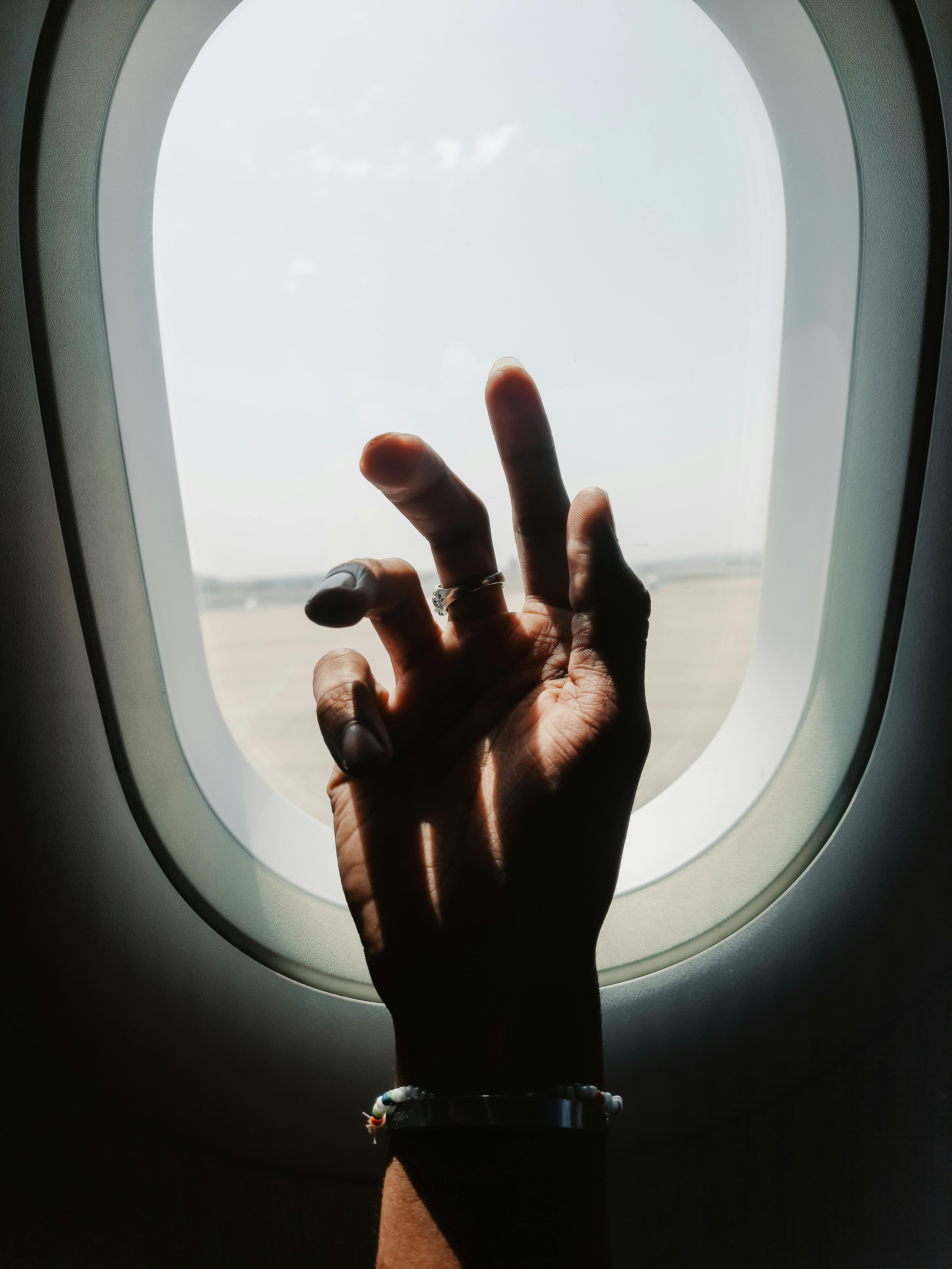 Hand of a Man against a Plane Window · Free Stock Photo