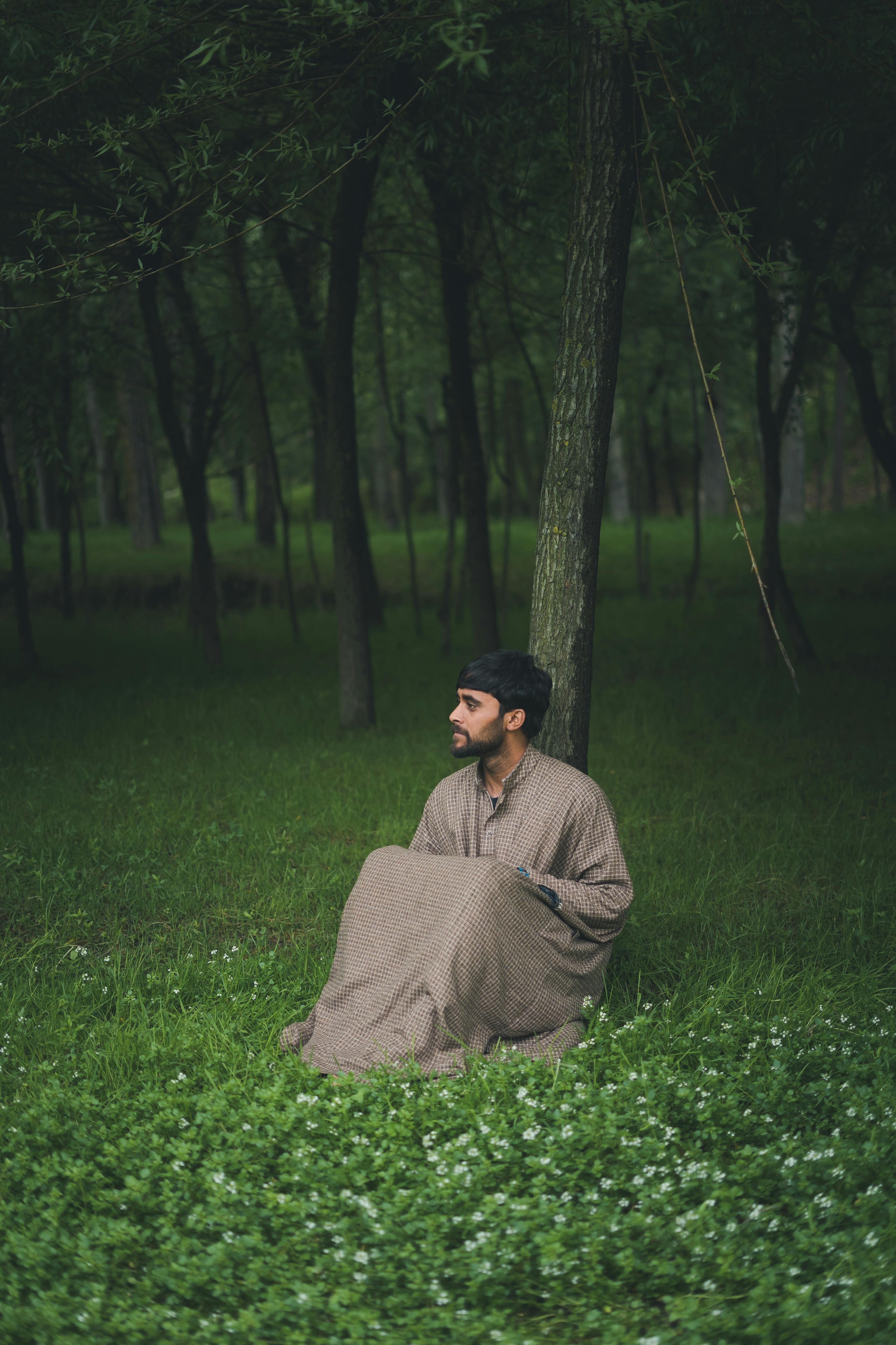 Man in Traditional Clothing Sitting in Forest · Free Stock Photo