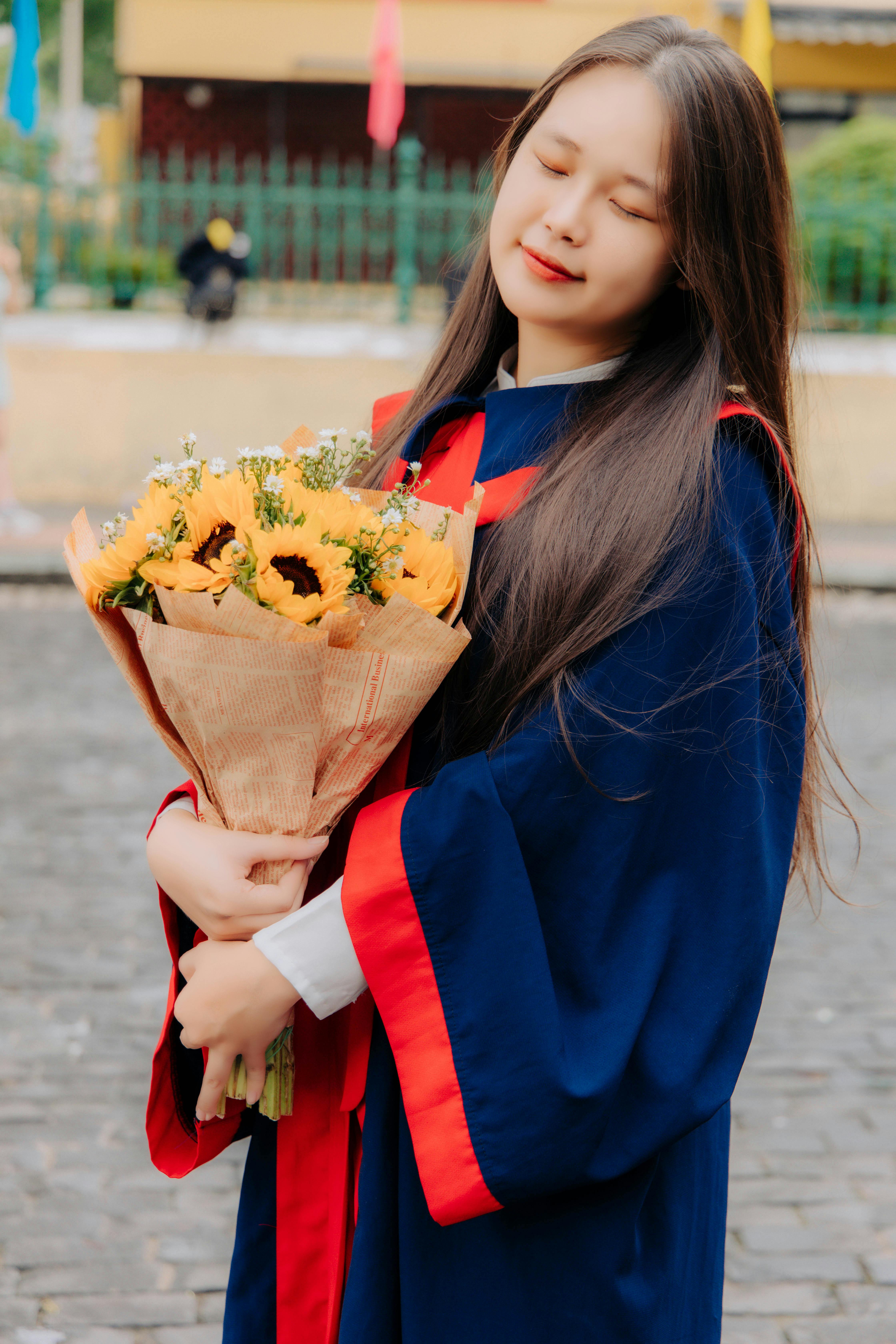 Portrait of Graduate with Flowers and in Gown · Free Stock Photo