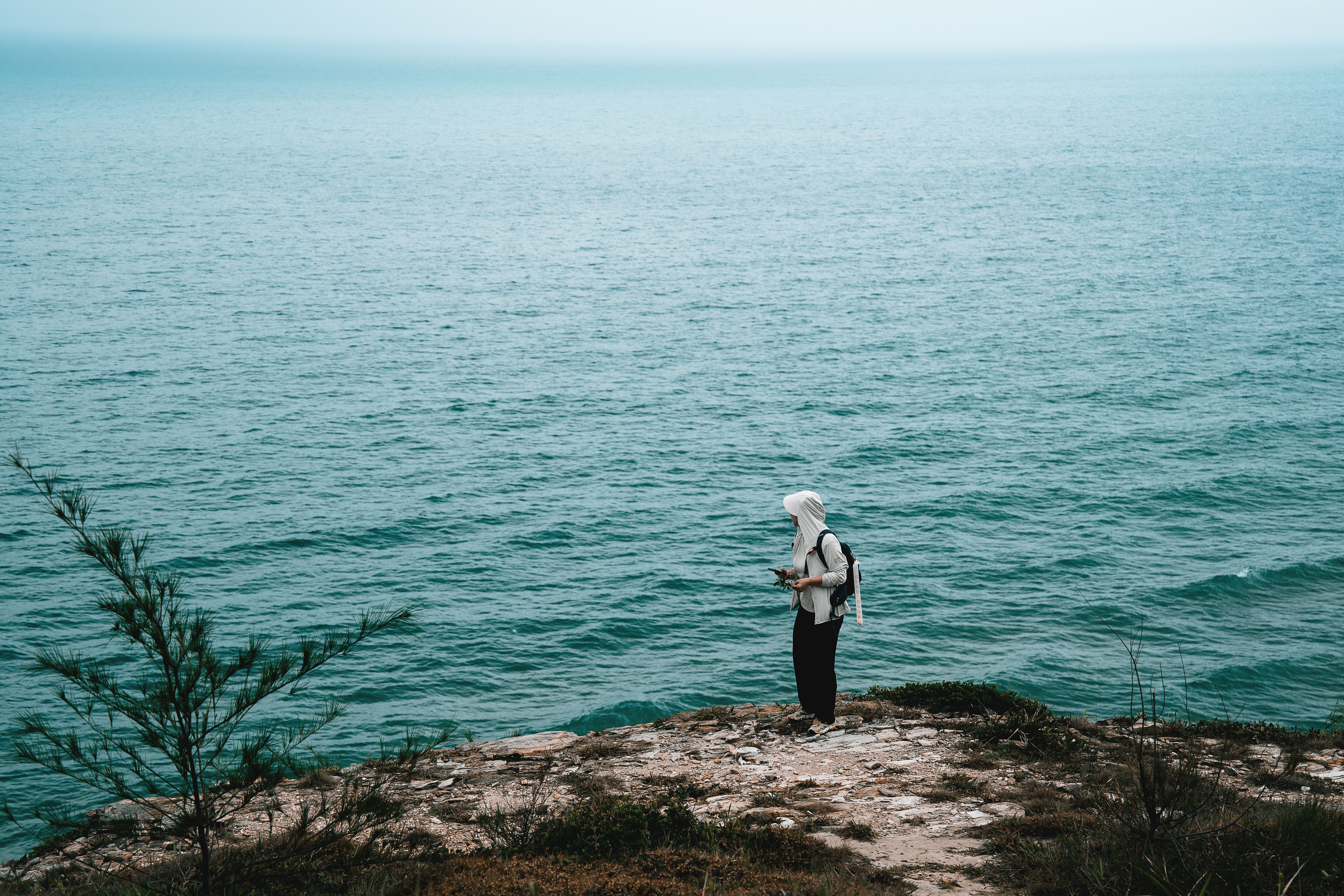 Woman Standing on Cliff near Sea · Free Stock Photo
