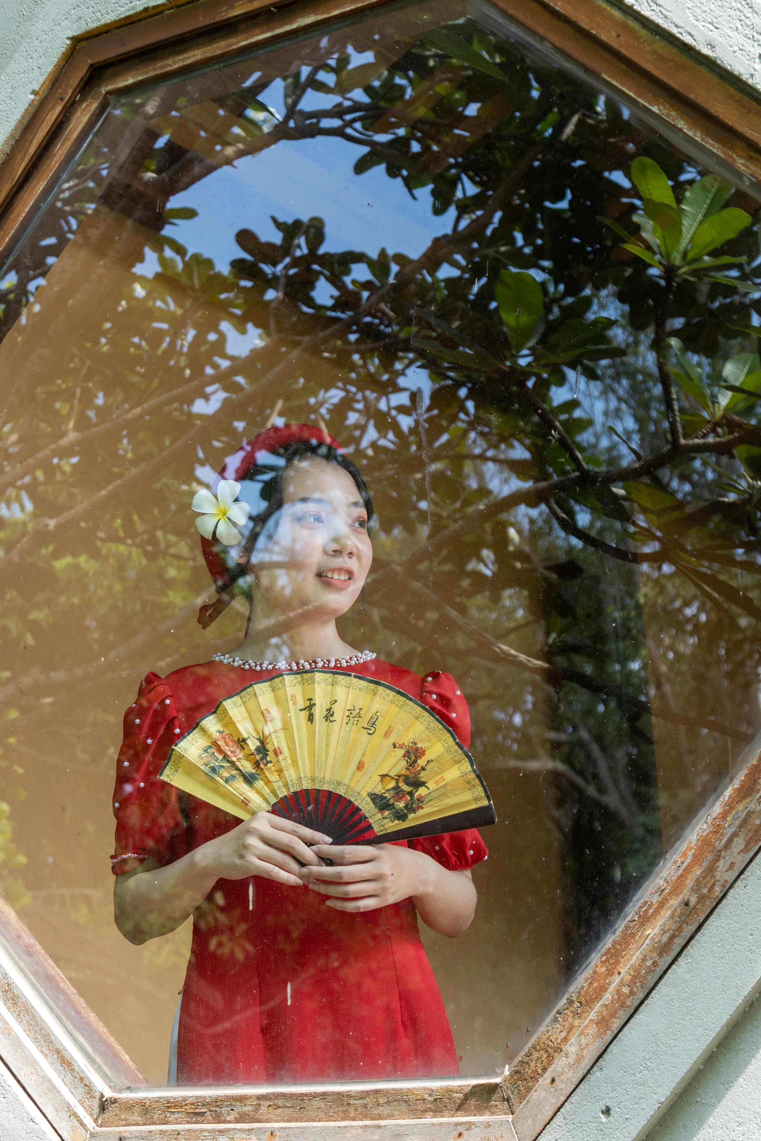Woman with Fan Posing behind Window · Free Stock Photo