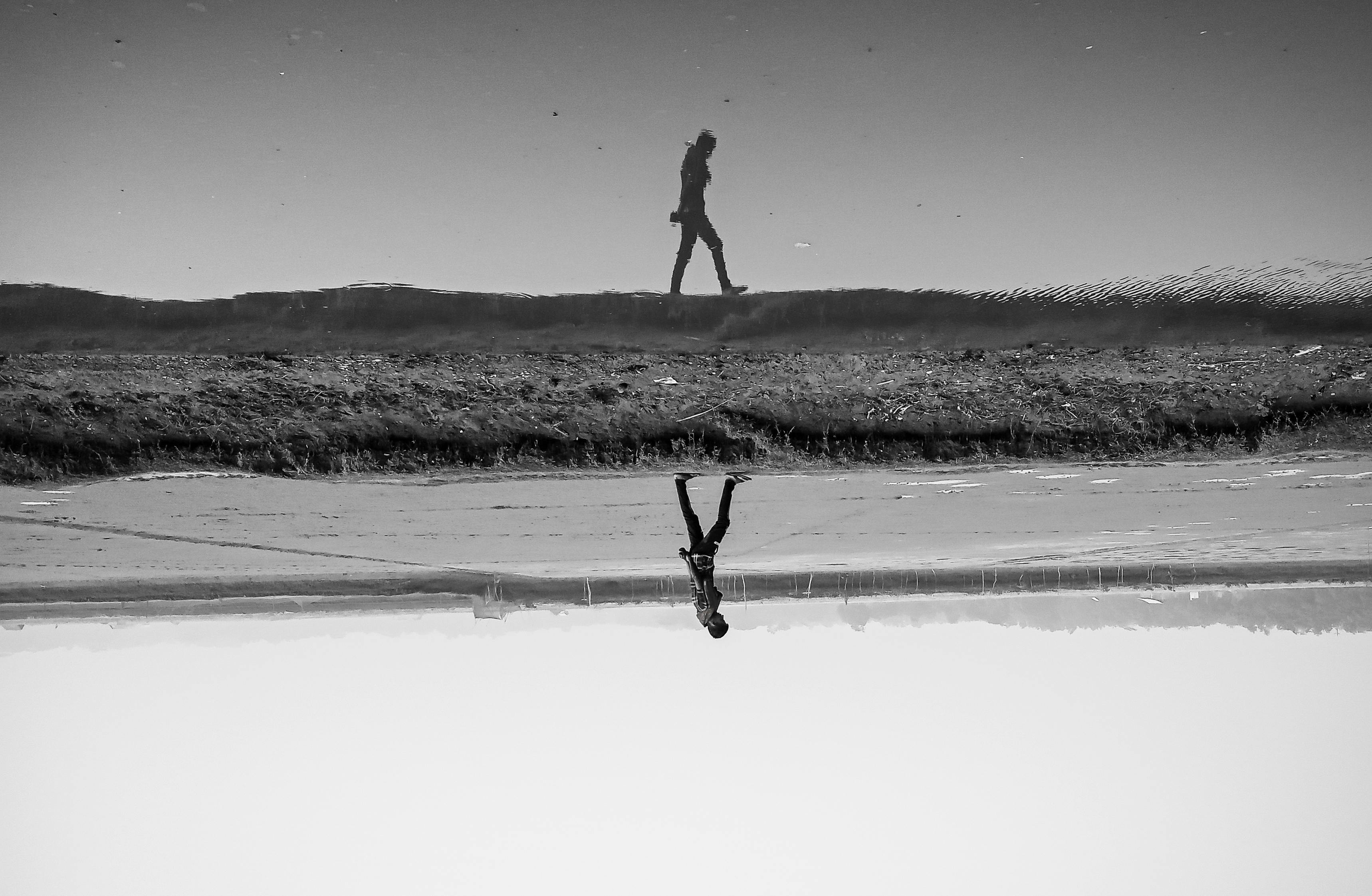 Upside Down Reflection of a Young Man Walking near Water · Free Stock Photo