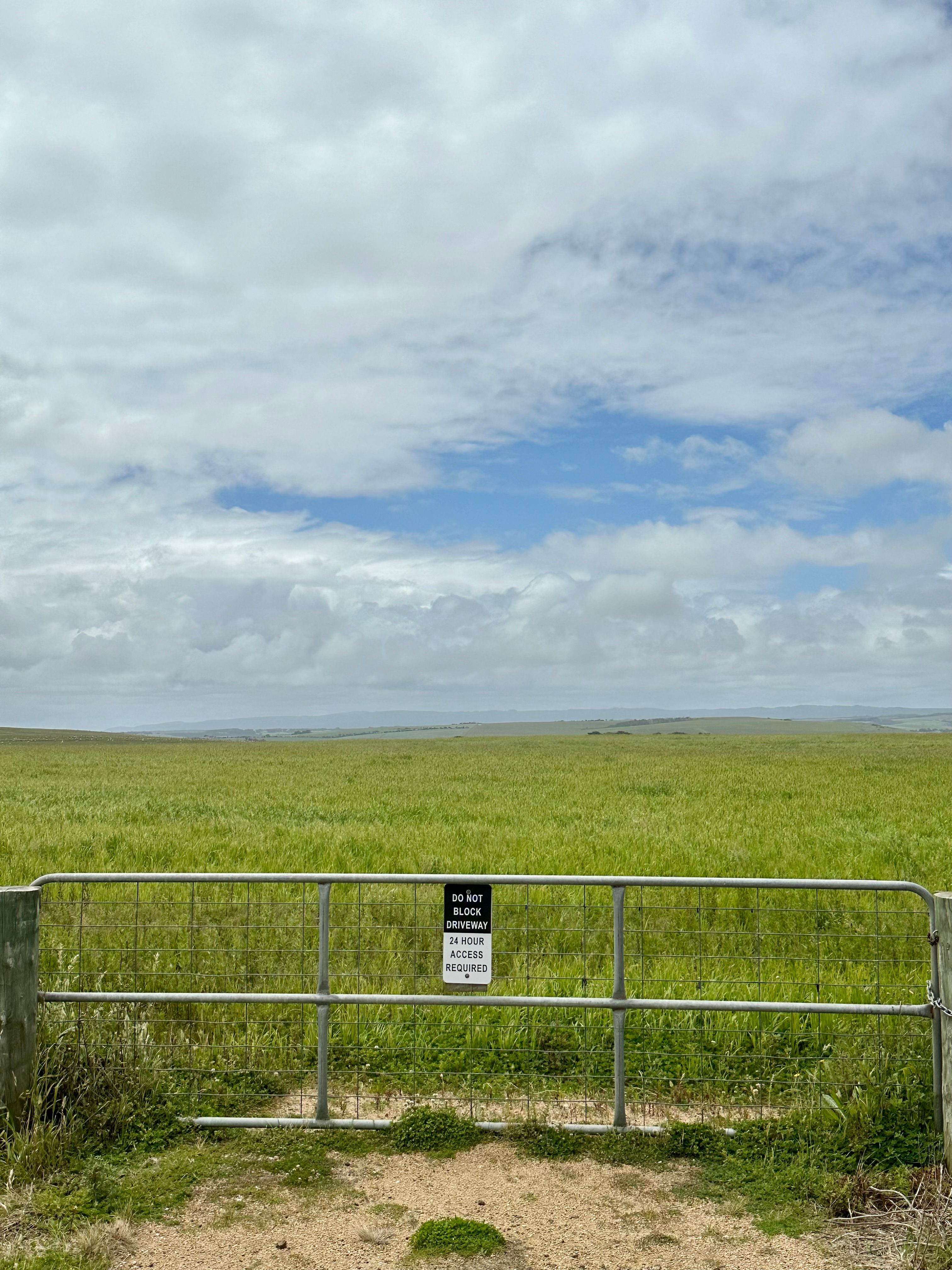 Green Agricultural Field and a Notice on a Metal Fence · Free Stock Photo