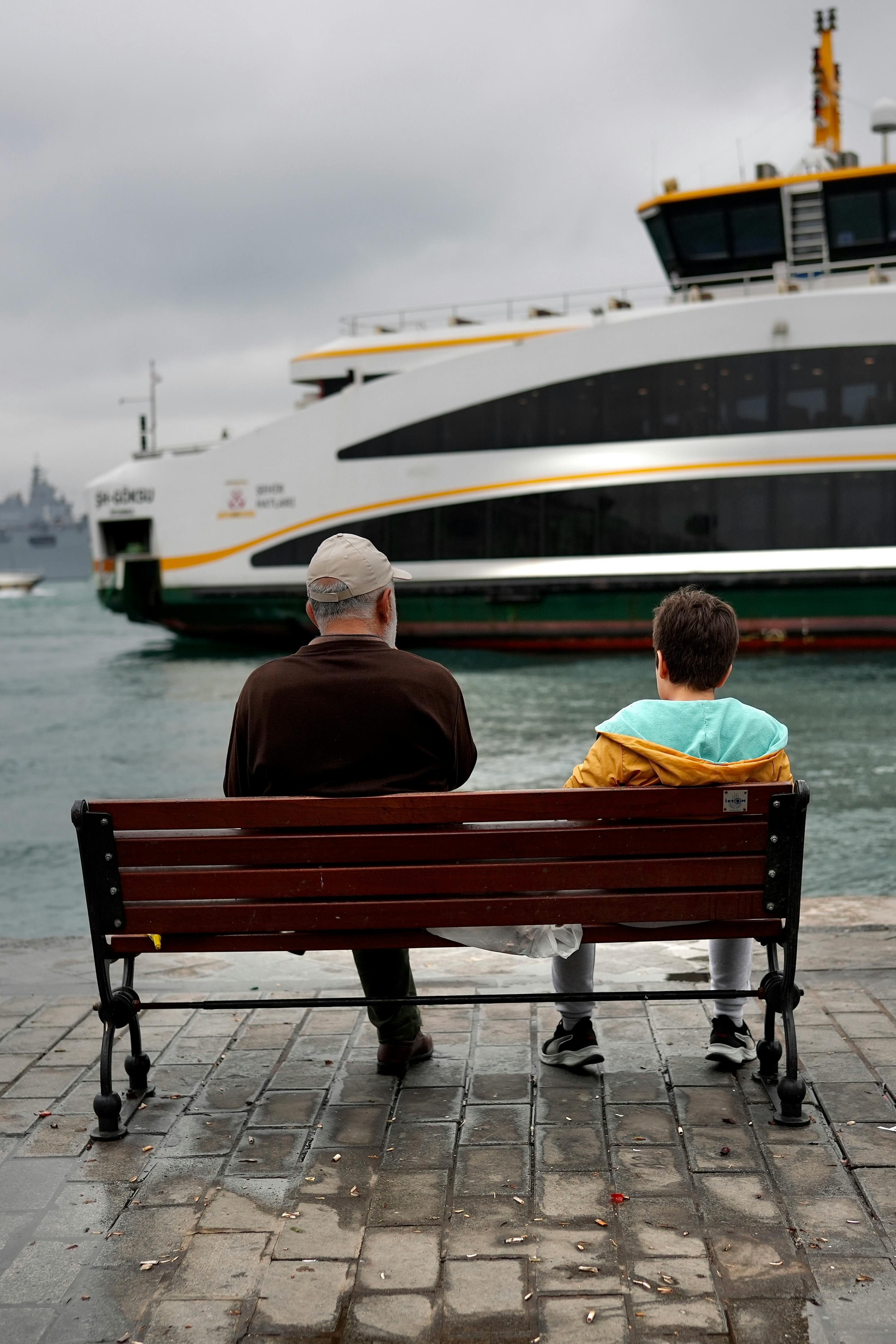 Back View of a Man and a Boy Sitting on a Bench near the Harbor in City ...