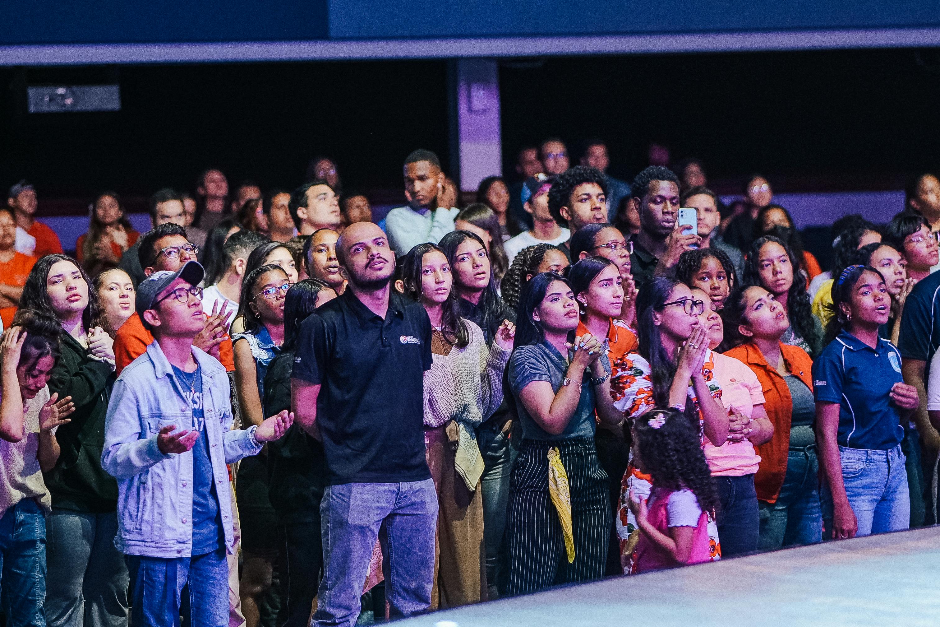 Congregation Standing in front of a Stage and Praying · Free Stock Photo