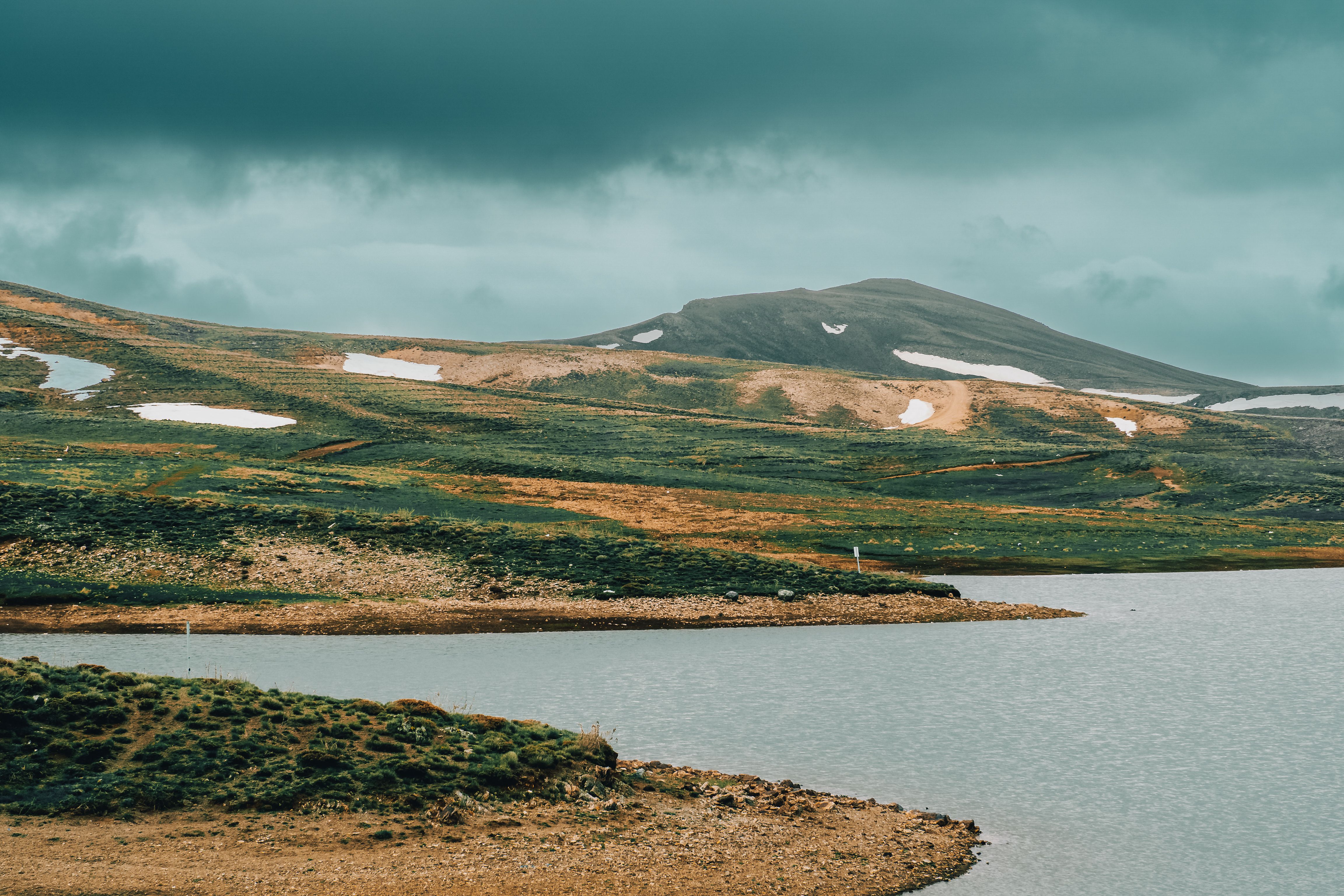 Scenic View of a Lake and Hills and Fields under an Overcast Sky · Free ...