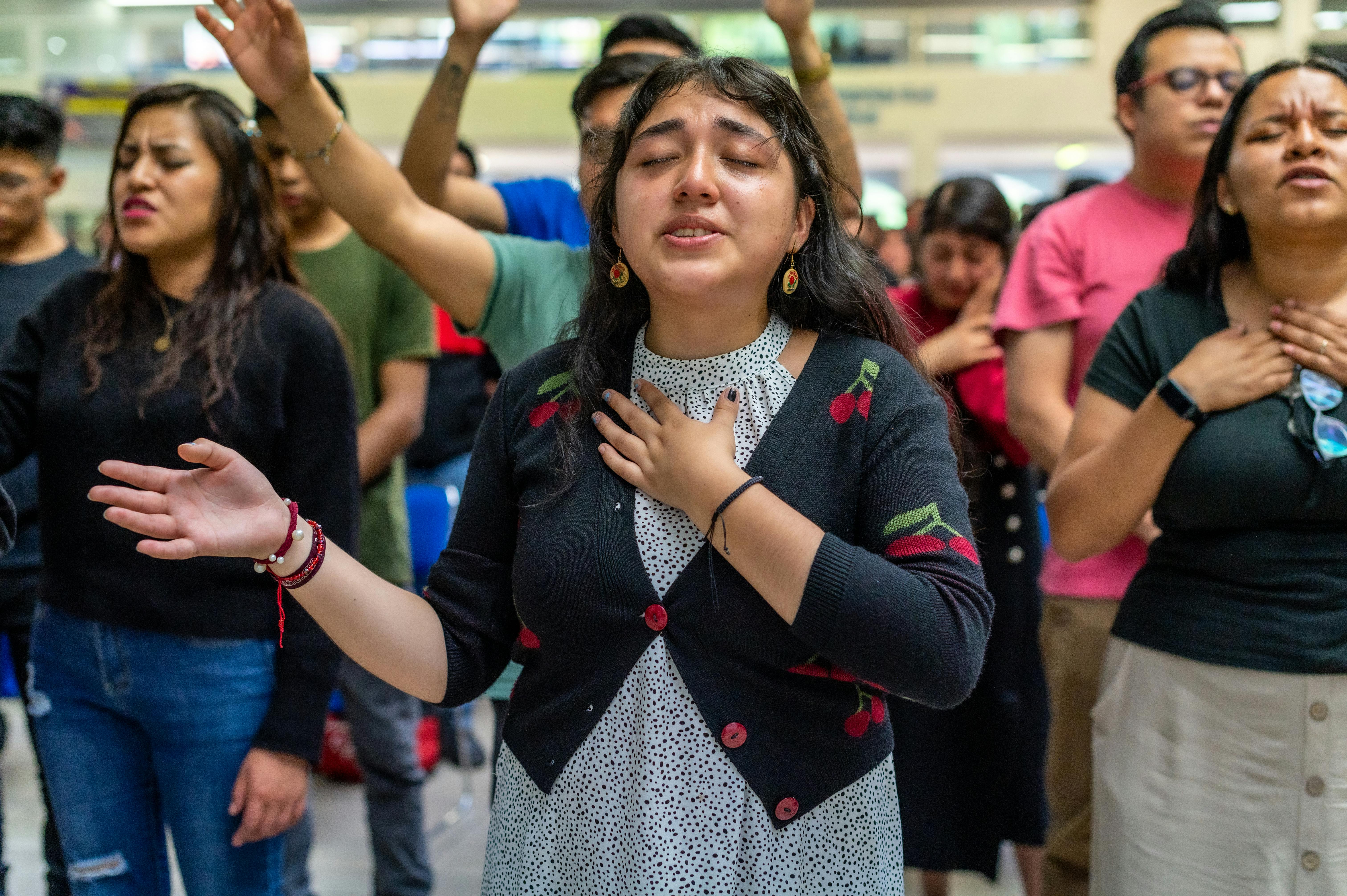 A woman is praying in a crowd of people · Free Stock Photo