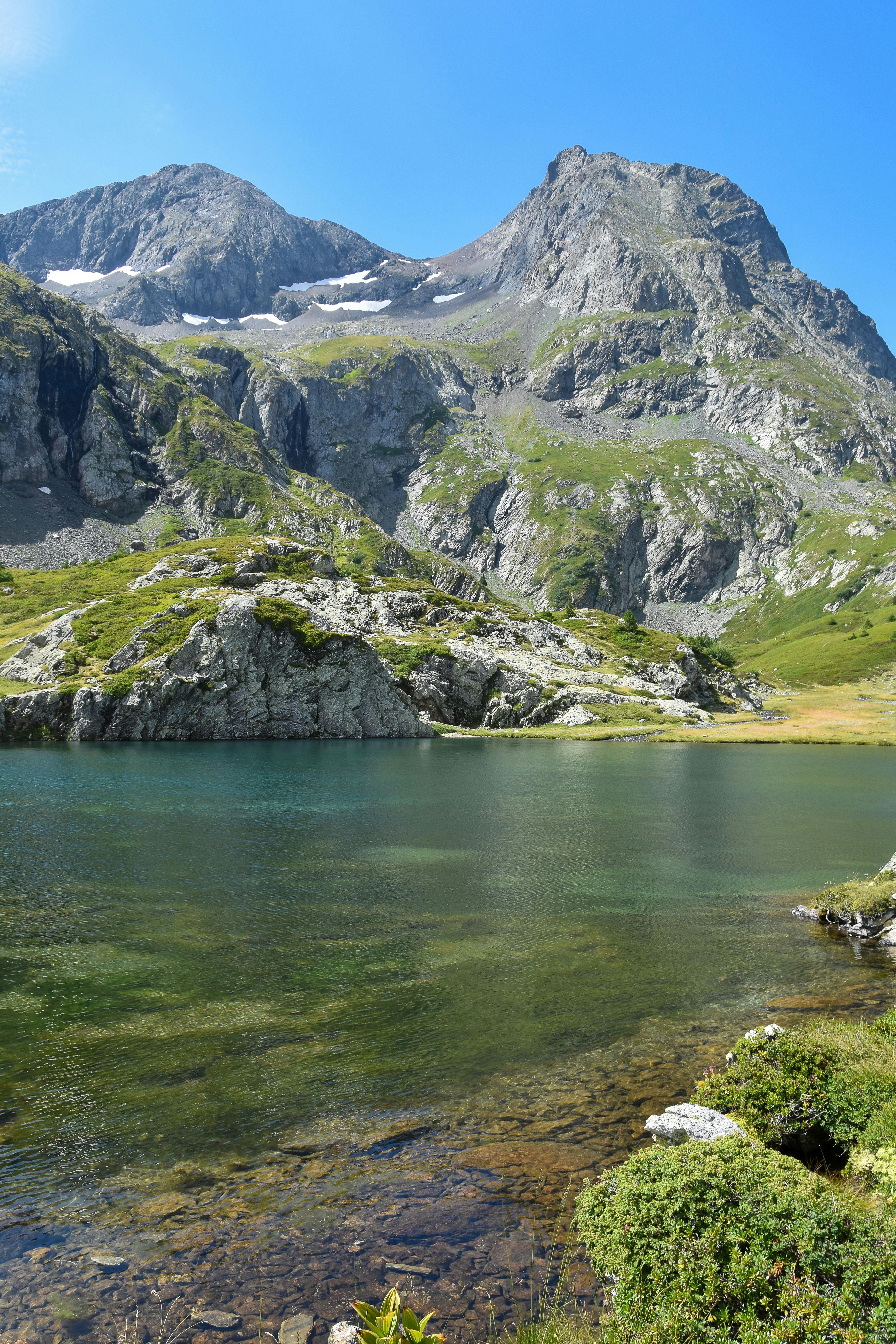 Body Of Water Near Mountain Under Clear Sky · Free Stock Photo