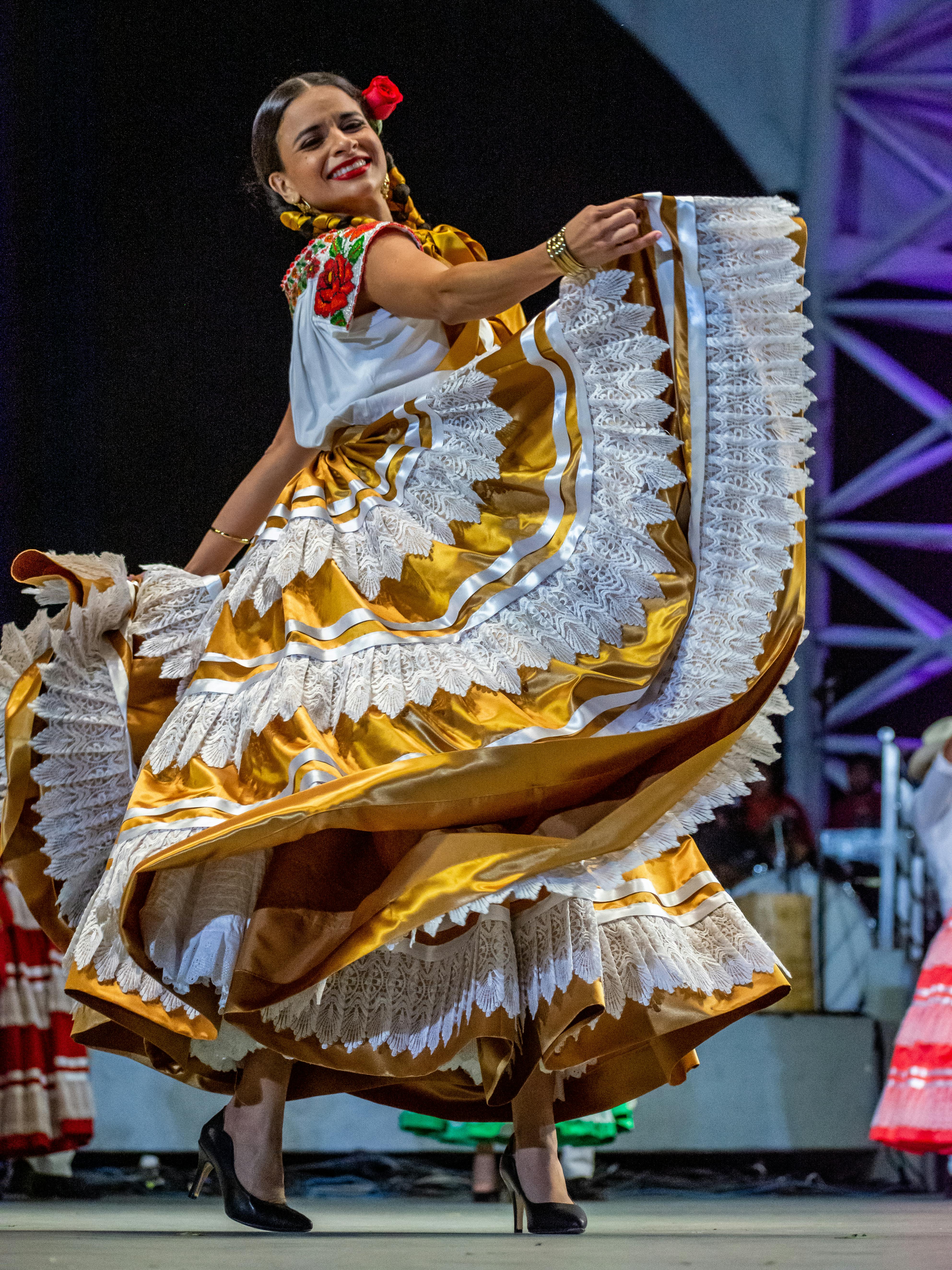 A woman in a mexican dress dancing on stage · Free Stock Photo