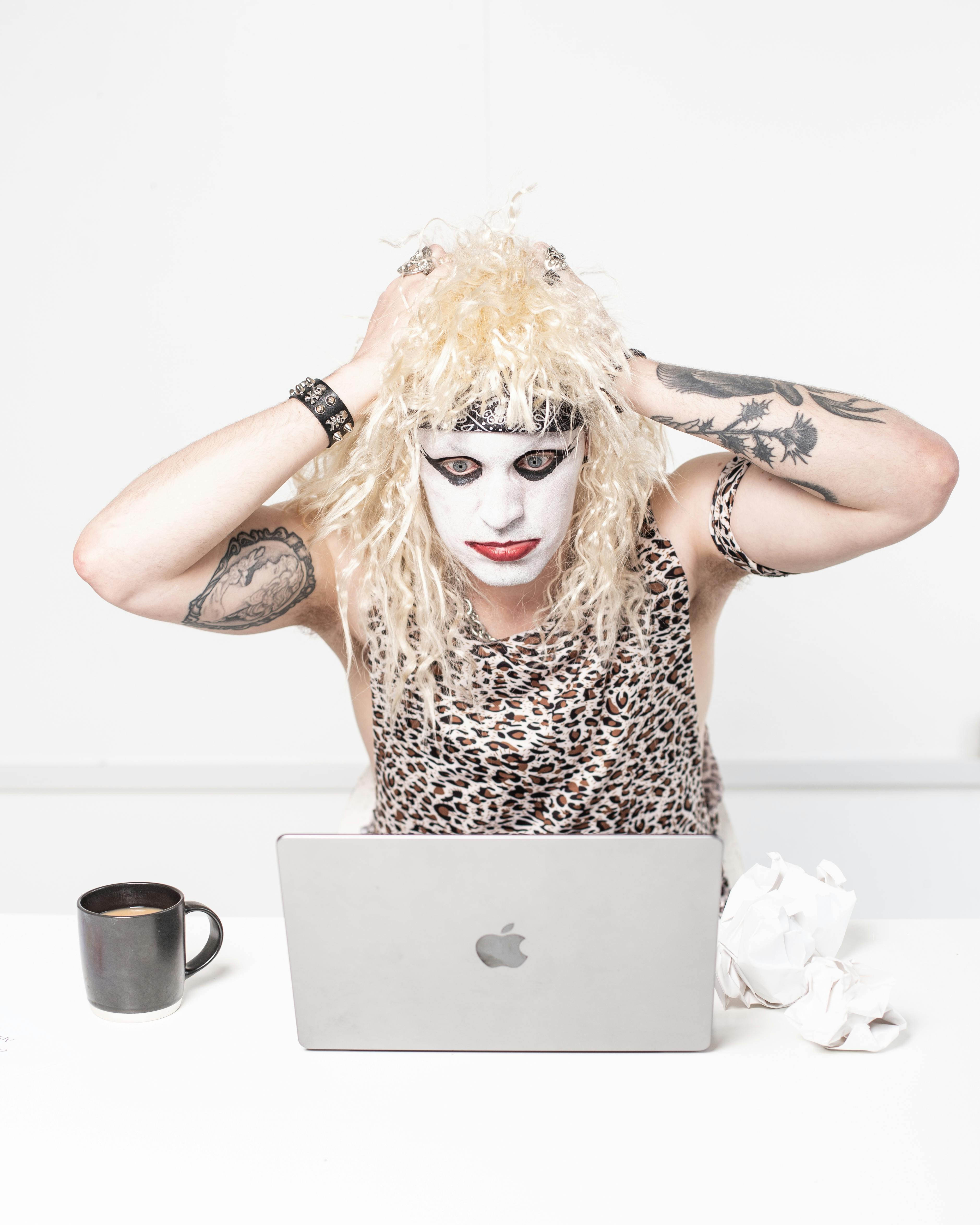 Man in Goth Style Clothes and Makeup Sitting in front of a Laptop ...