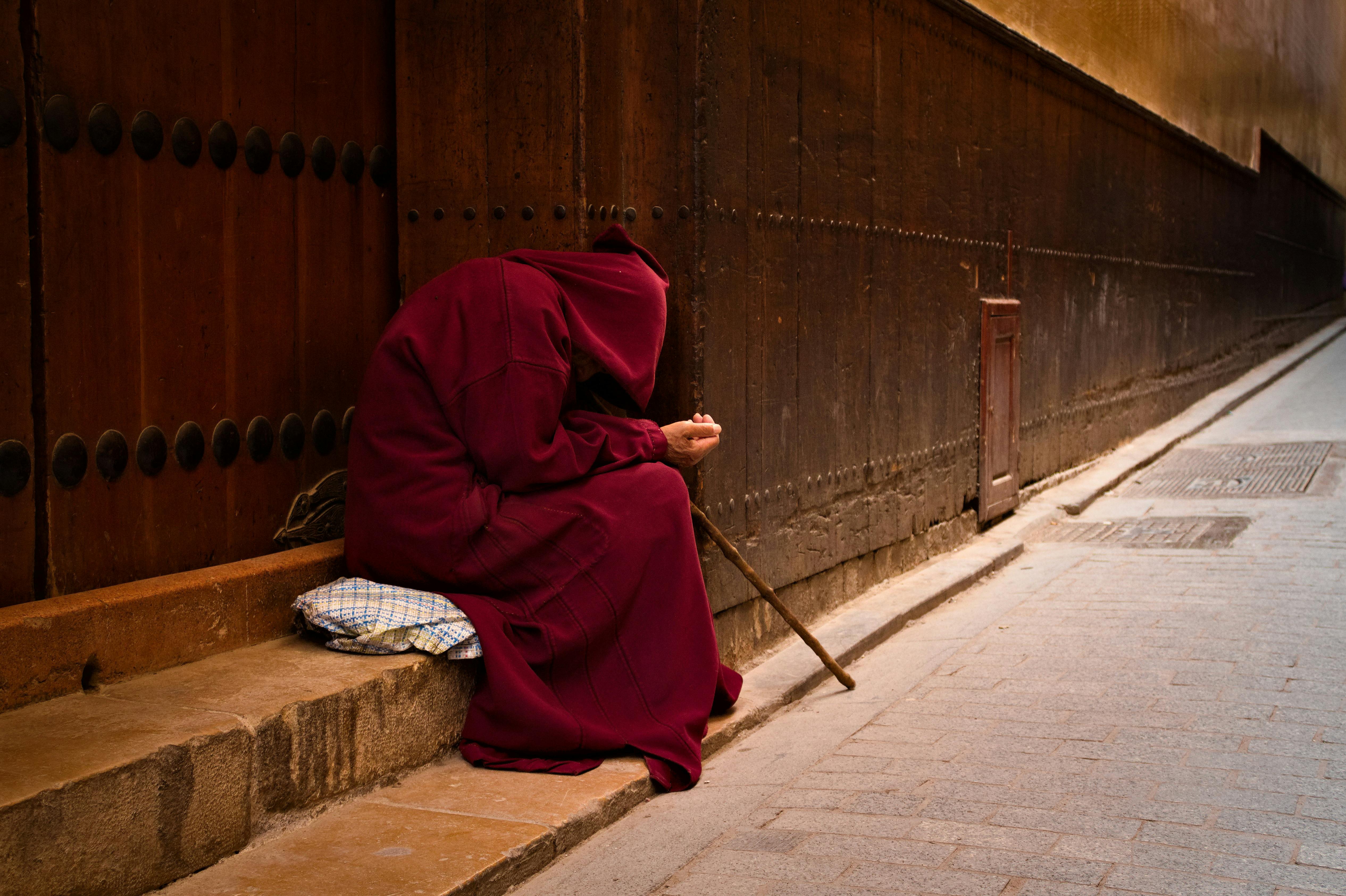 Beggar in Red Robes Sitting on Stairs · Free Stock Photo