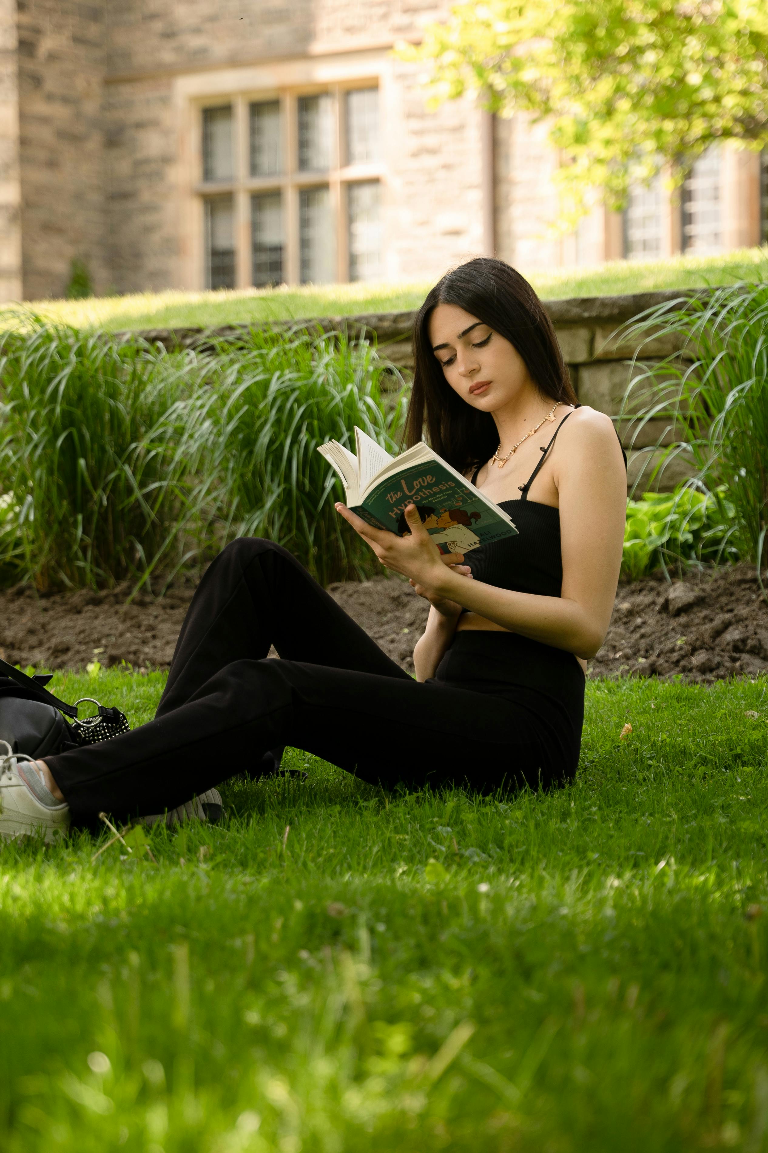 Woman Sitting and Reading Book on Grassland · Free Stock Photo