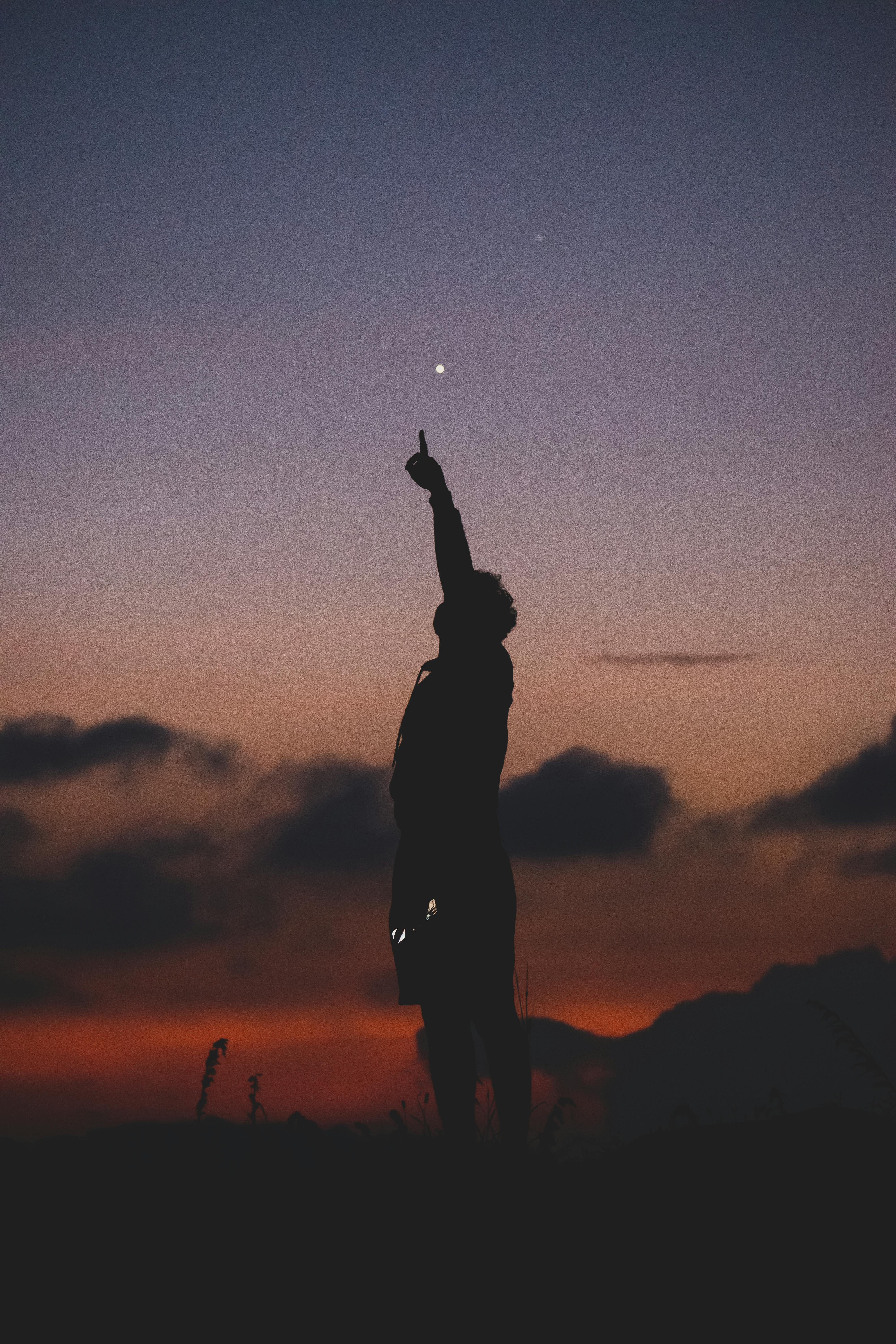 Man Standing with Arm Raised at Sunset · Free Stock Photo