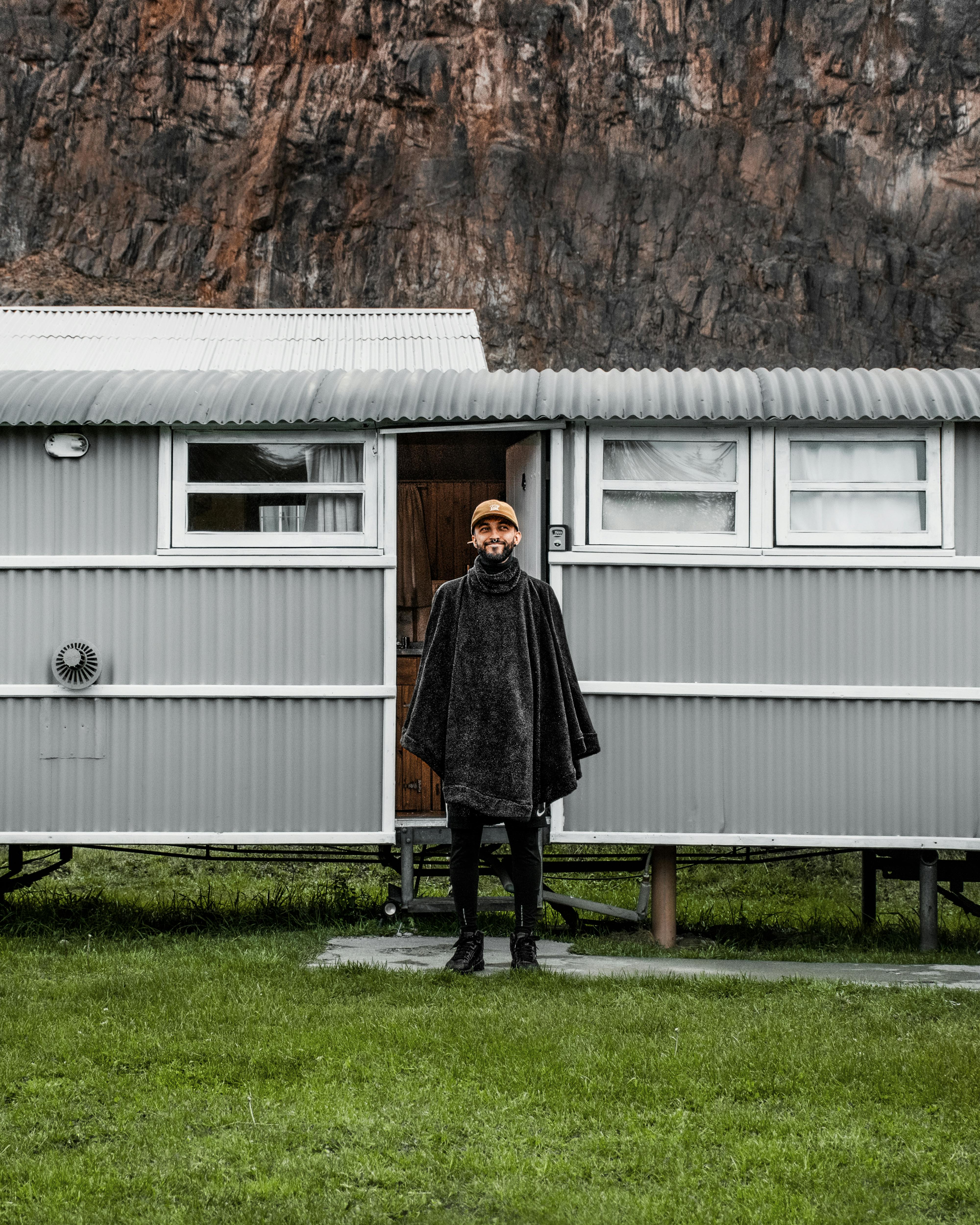 A Smiling Man Standing in front of a Tiny House · Free Stock Photo