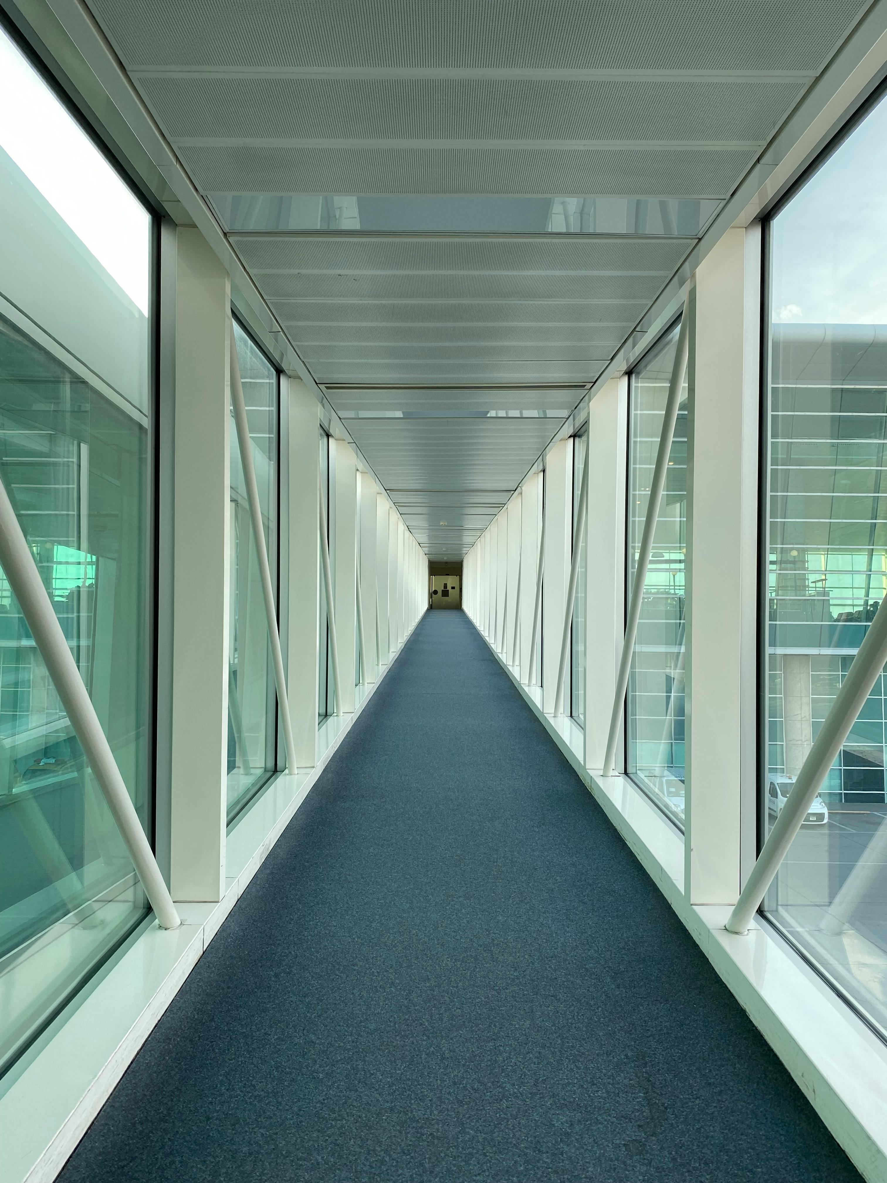 Glass and Steel Corridor Leading to an Airport Terminal · Free Stock Photo