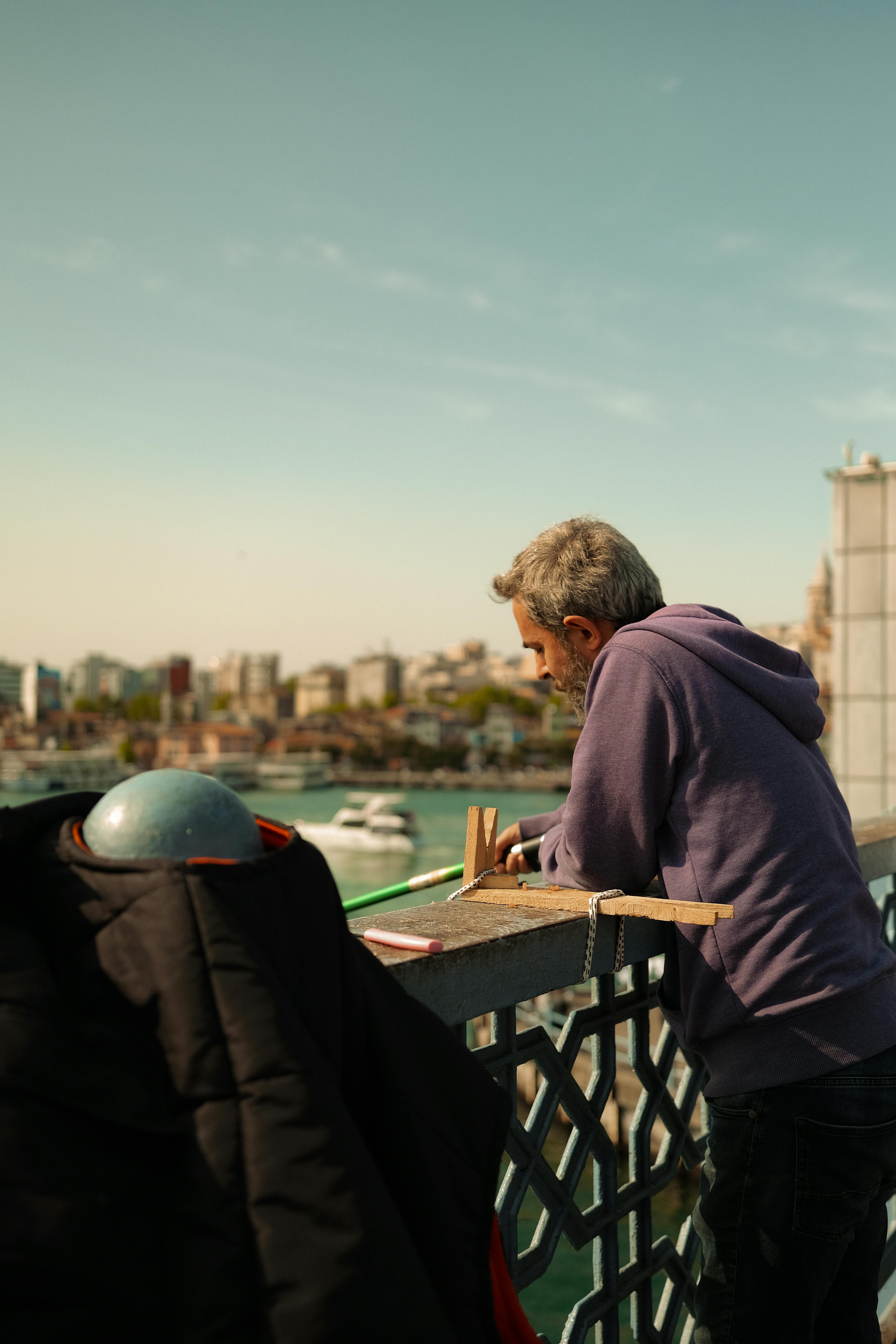 Man Resting against Bridge Railing Holding Fishing Rod · Free Stock Photo