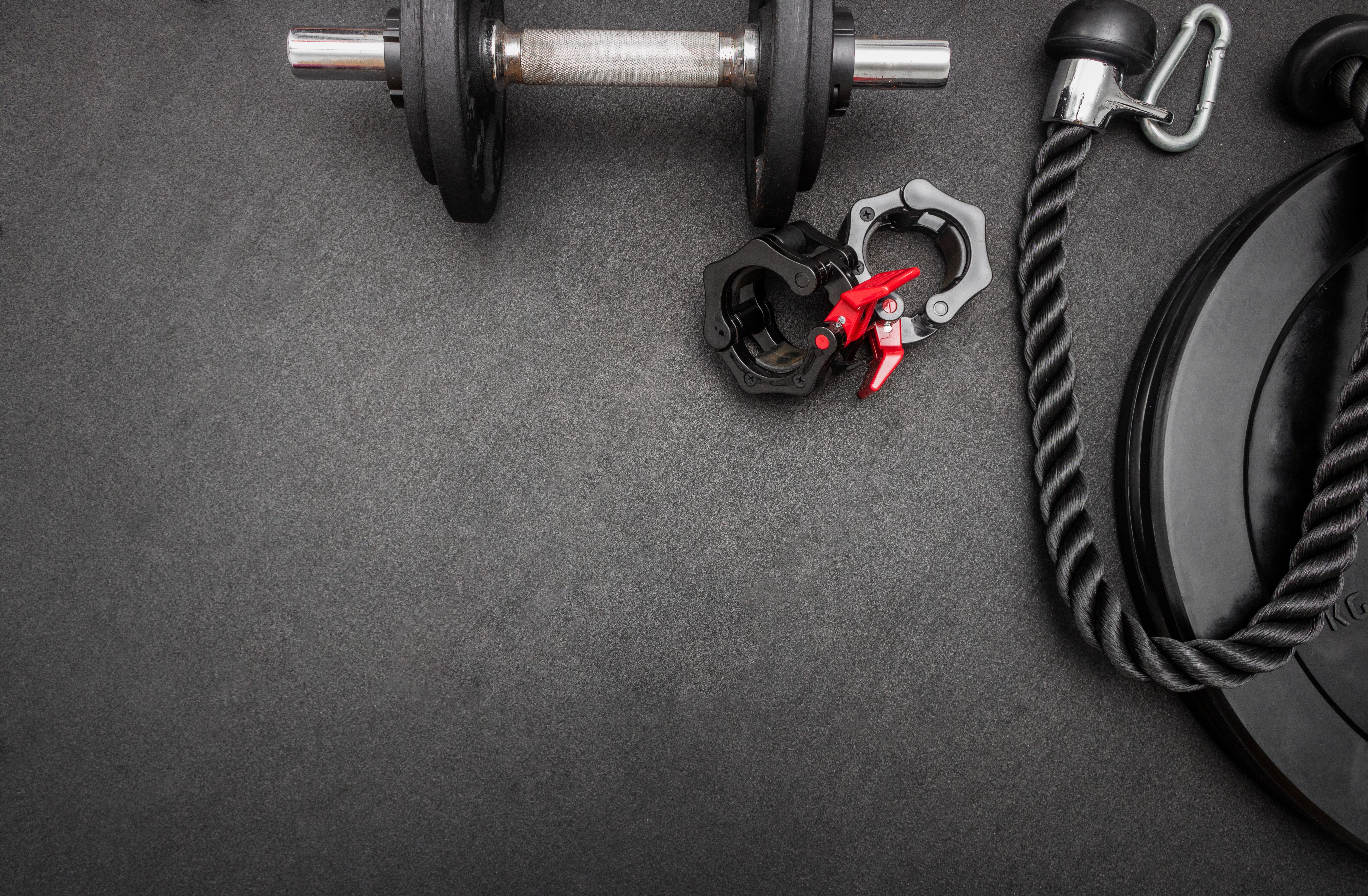 Barbell, dumbbells, triceps rope and clamps on the floor at the gym ...