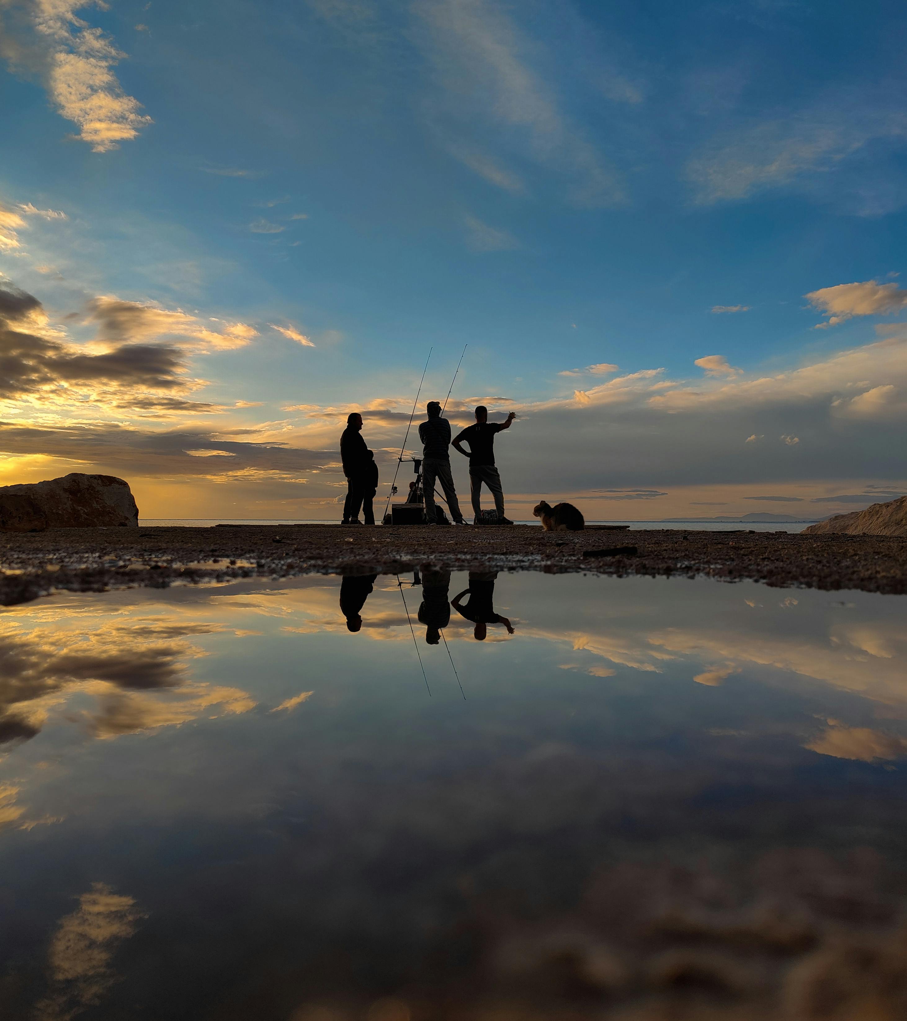 A Group of Fishermen Standing on the Shore at Sunset · Free Stock Photo