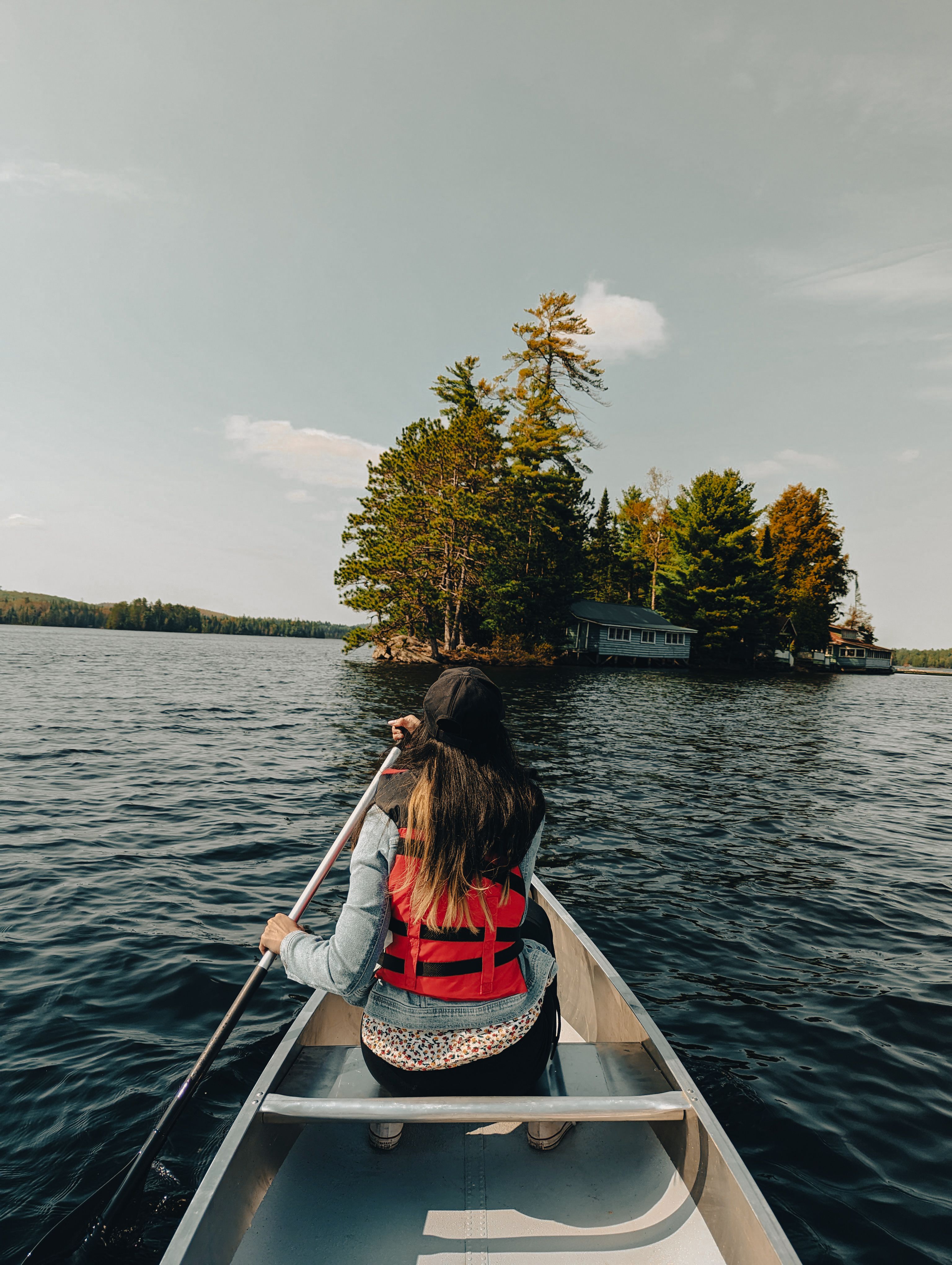 Woman Paddling in Boat to Island with Cottage · Free Stock Photo